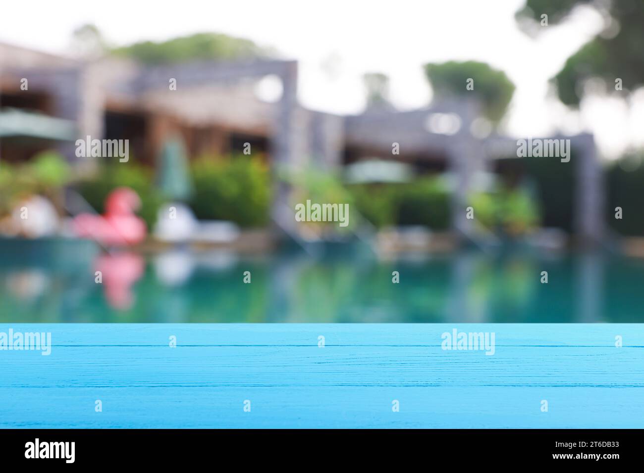 Empty light blue wooden desk near outdoor swimming pool at resort ...