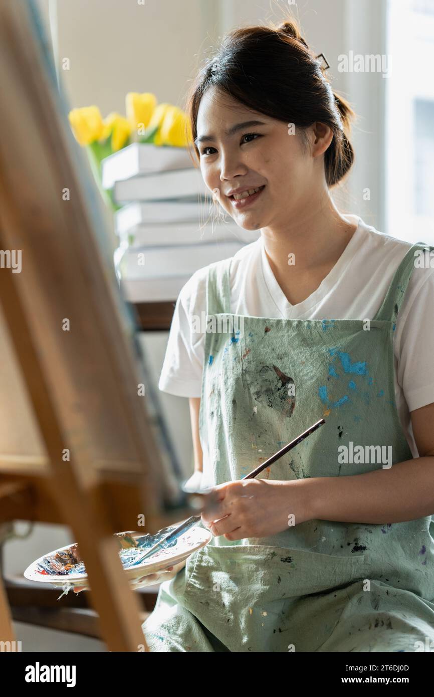 Female artist hold color palette and paintbrush for painting during ...