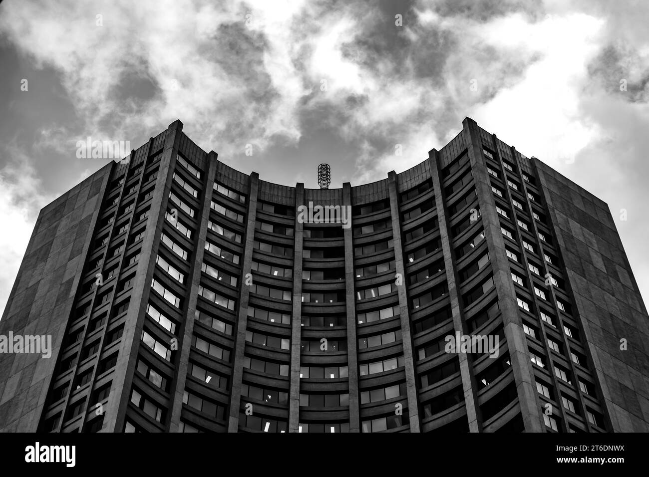 Bottom-up view of a tall curved symmetrical building in Black and White ...