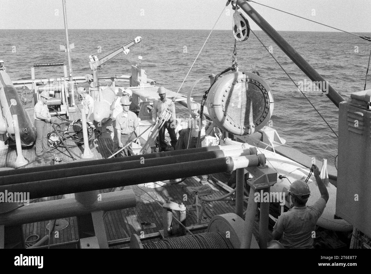 USS Illusive (MSO-448) lowers an acoustical device during an exercise ...