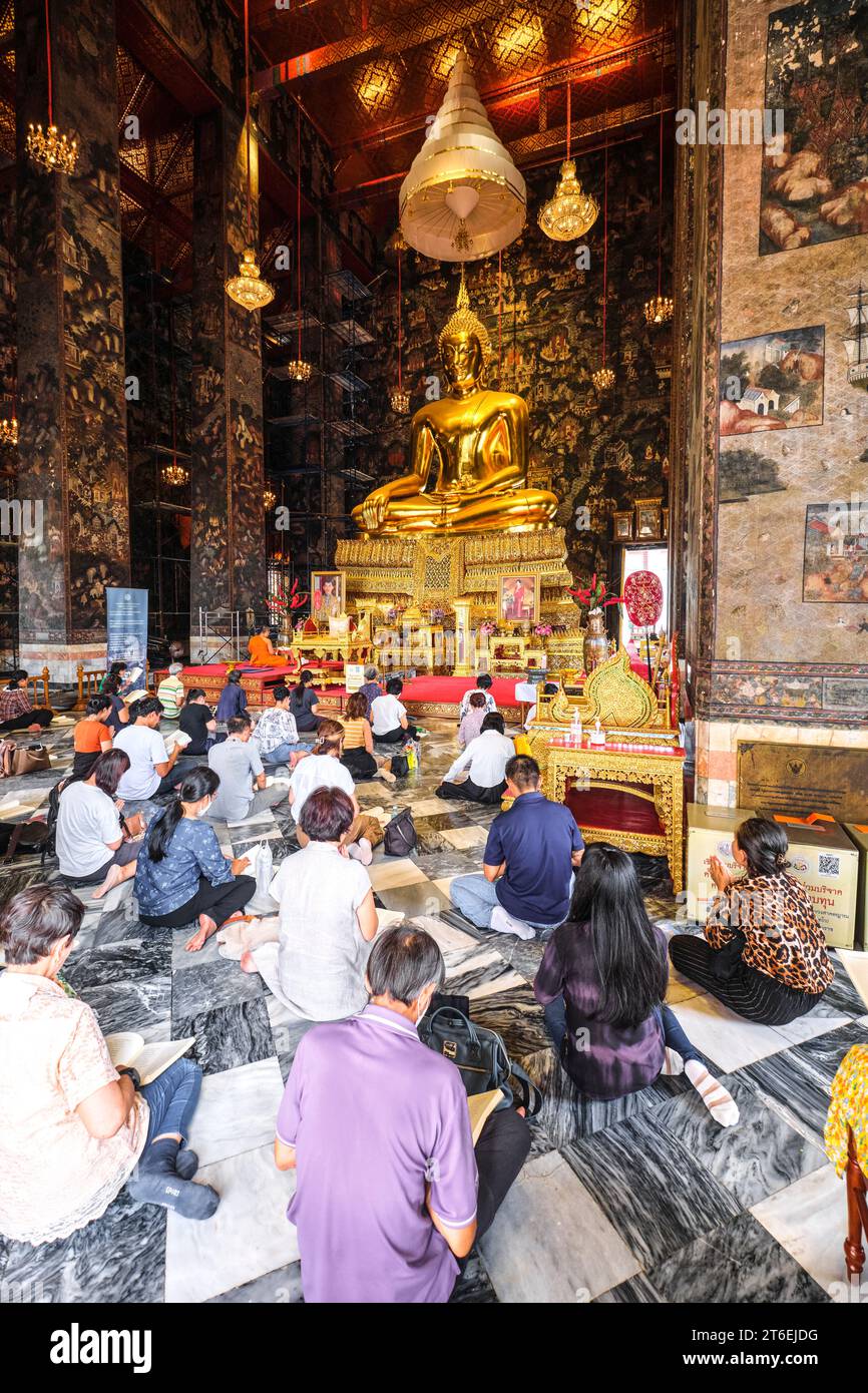 Worshippers crowd the inside of the temple, sitting on the ground and ...