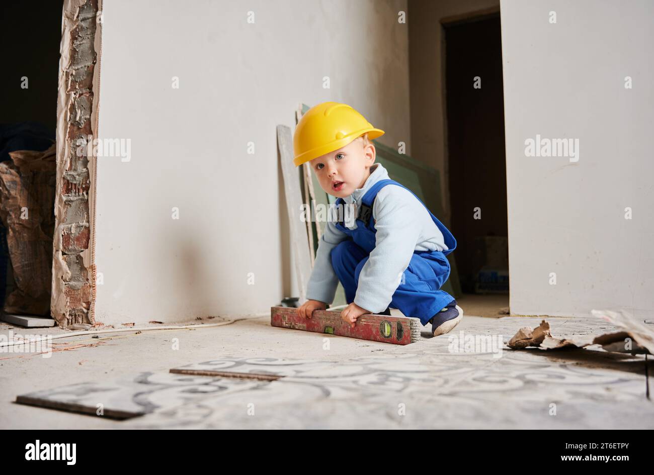 Adorable child construction worker crouching down and holding spirit ...