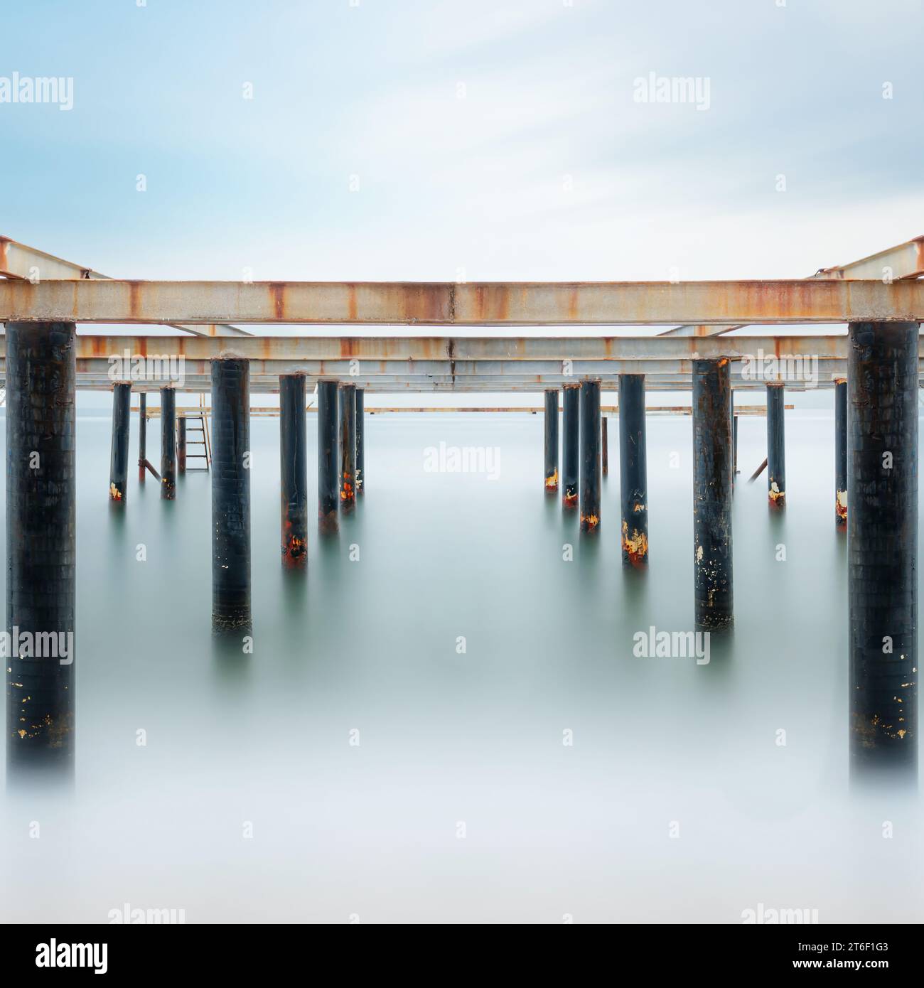 Fine art view of columns under metal pier at sunrise. Shot with long ...