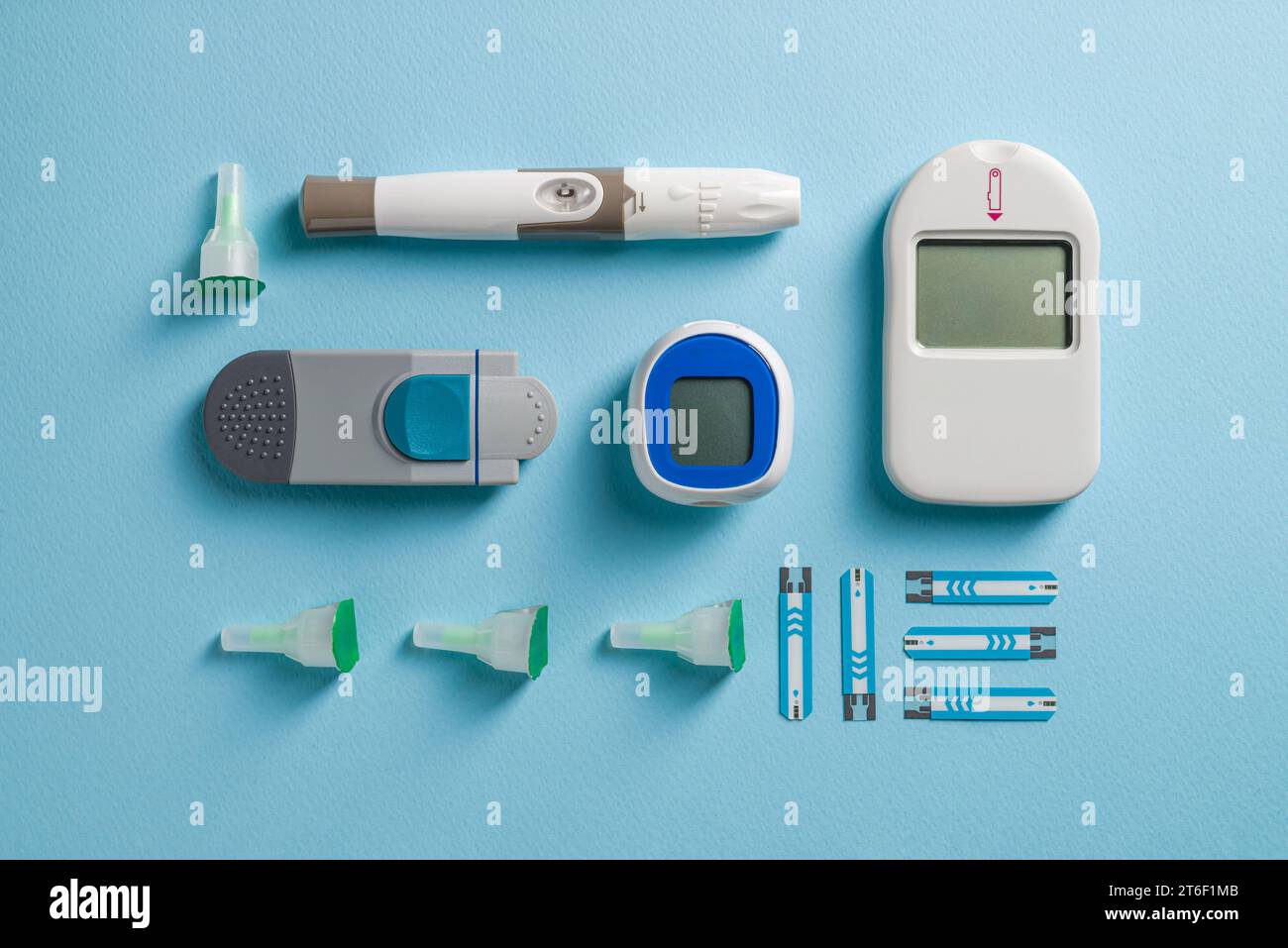 Top view of glucometer, lancet pen and strips on blue background ...