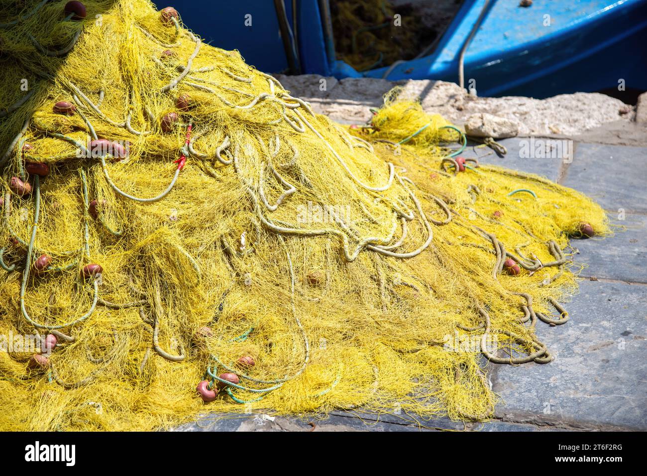 Fishing net pile on port ground drying under the sun. Yellow color ...