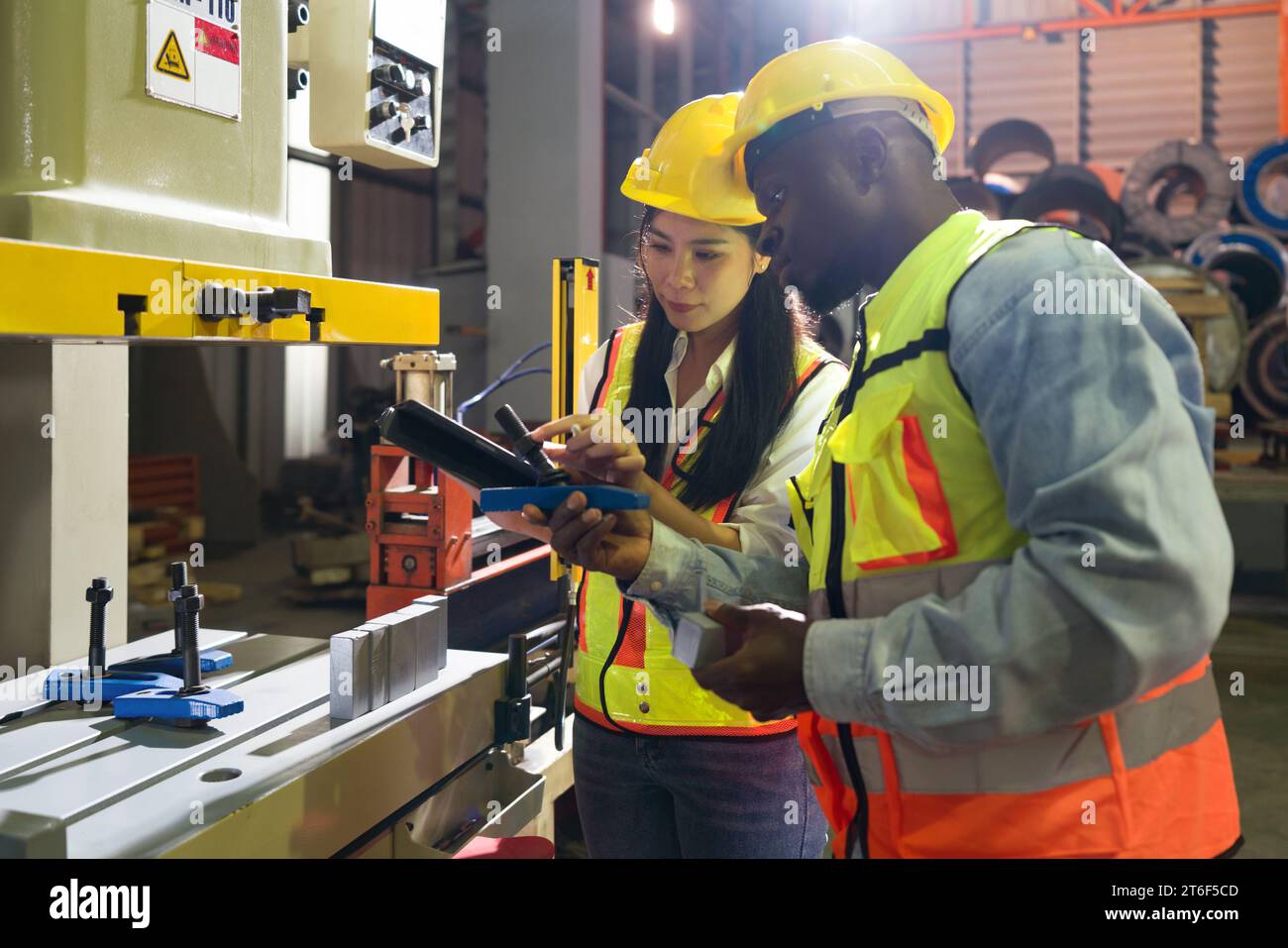 Two individuals are busily engaged with operating a large machine ...