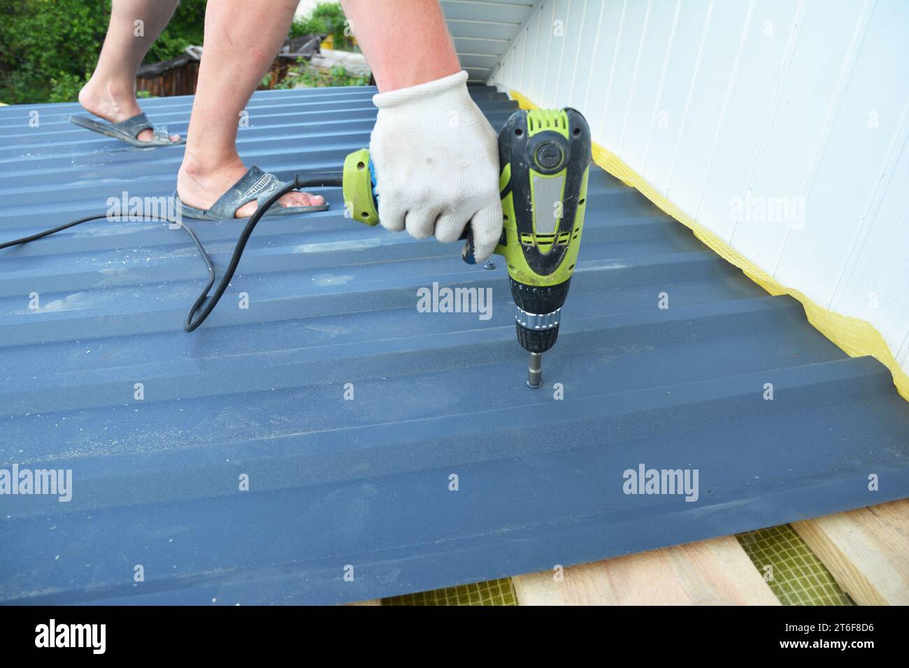 Roofing contractor laying metal roof sheet on the flat house rooftop ...