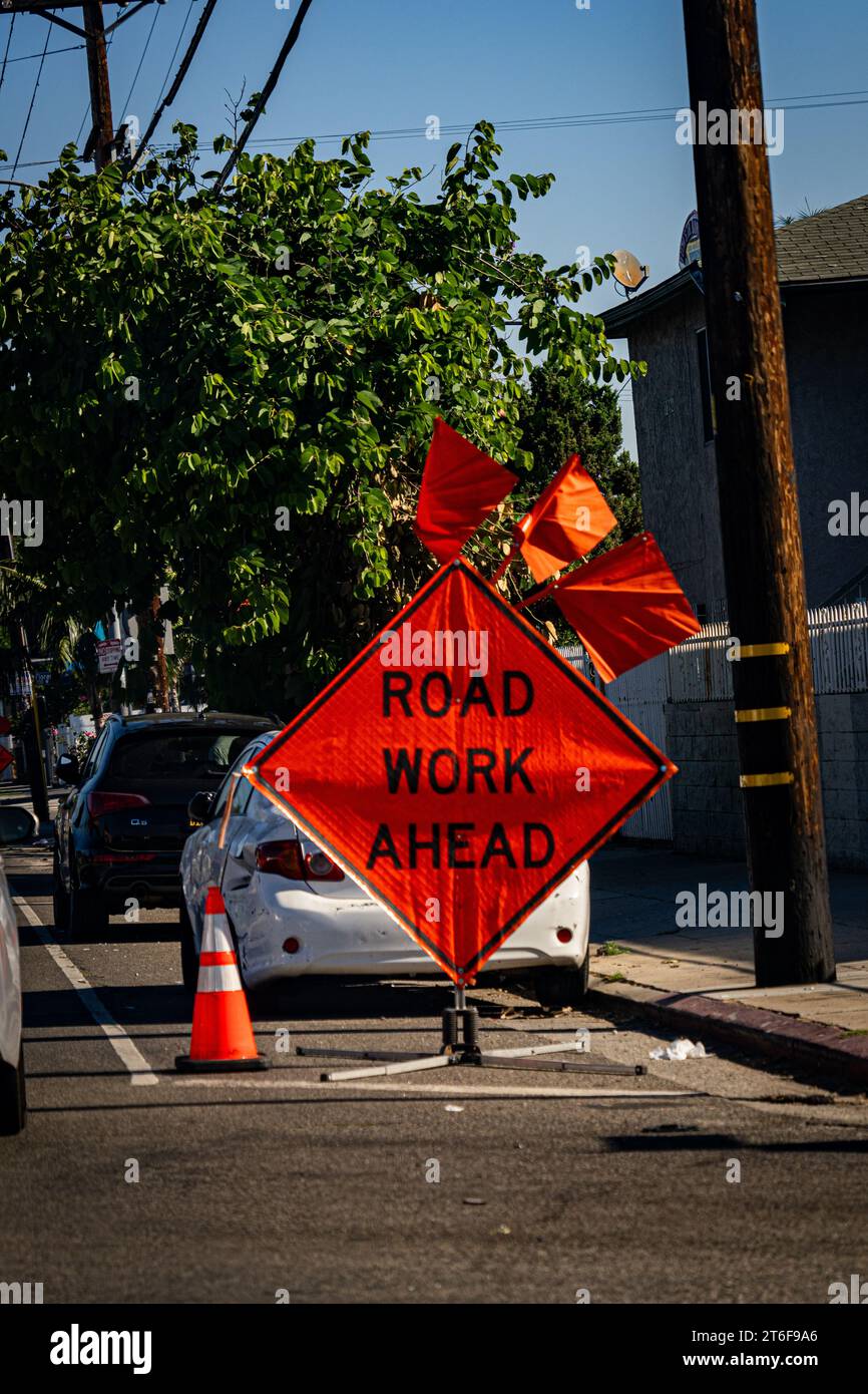 A work ahead sign is seen on a road surrounded by parked cars Stock ...