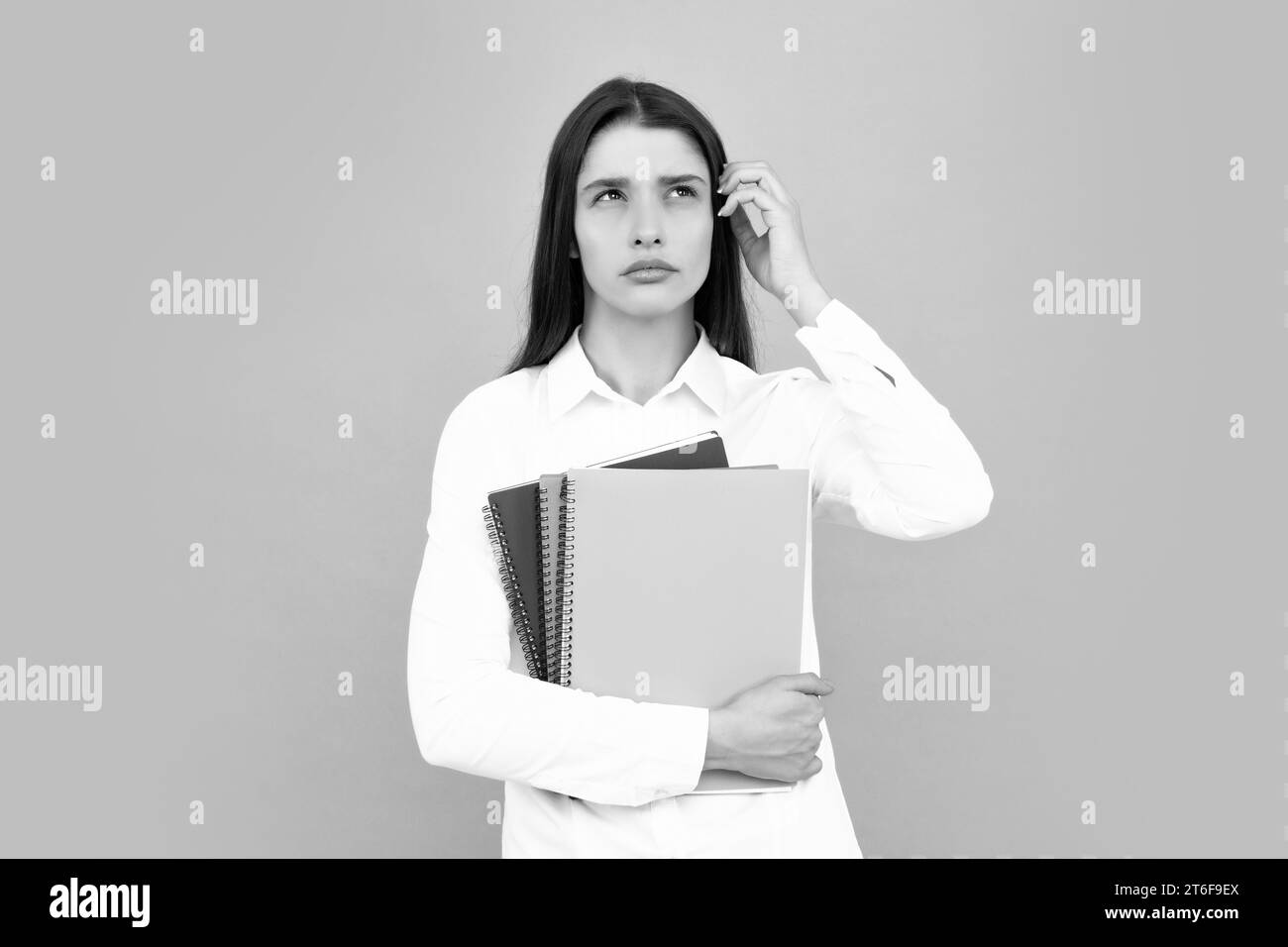 Angry young woman college student holding book on isolated gray ...