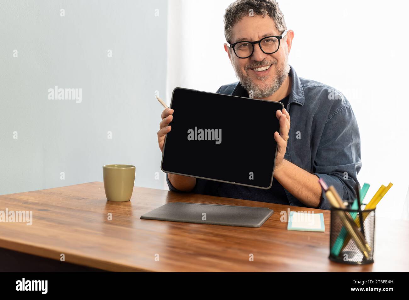 A cheerful fifty-year-old man confidently showing the screen of his ...