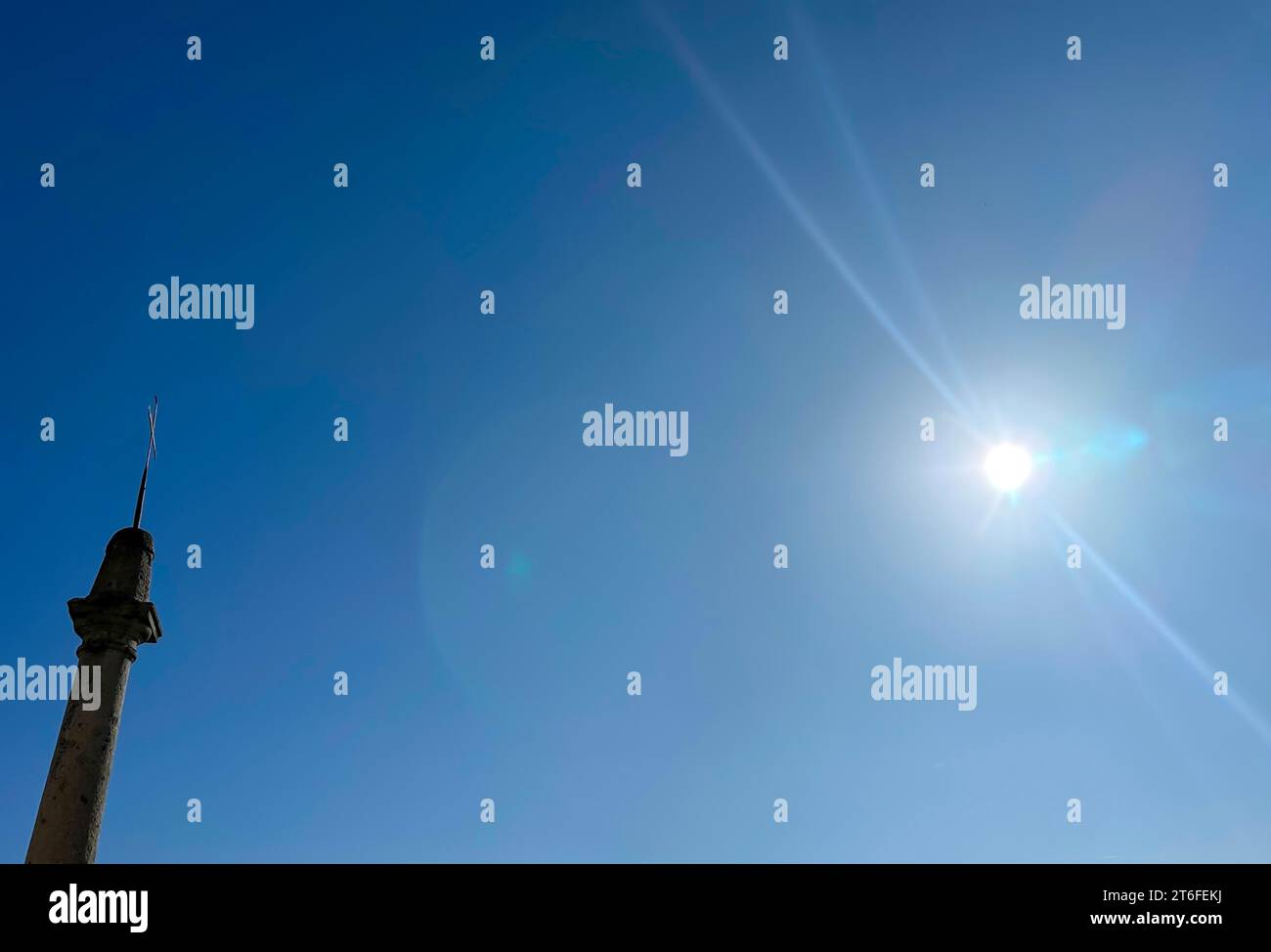 Column with a Cross Against Blue Clear Sky and the Sun with Lens Flare ...