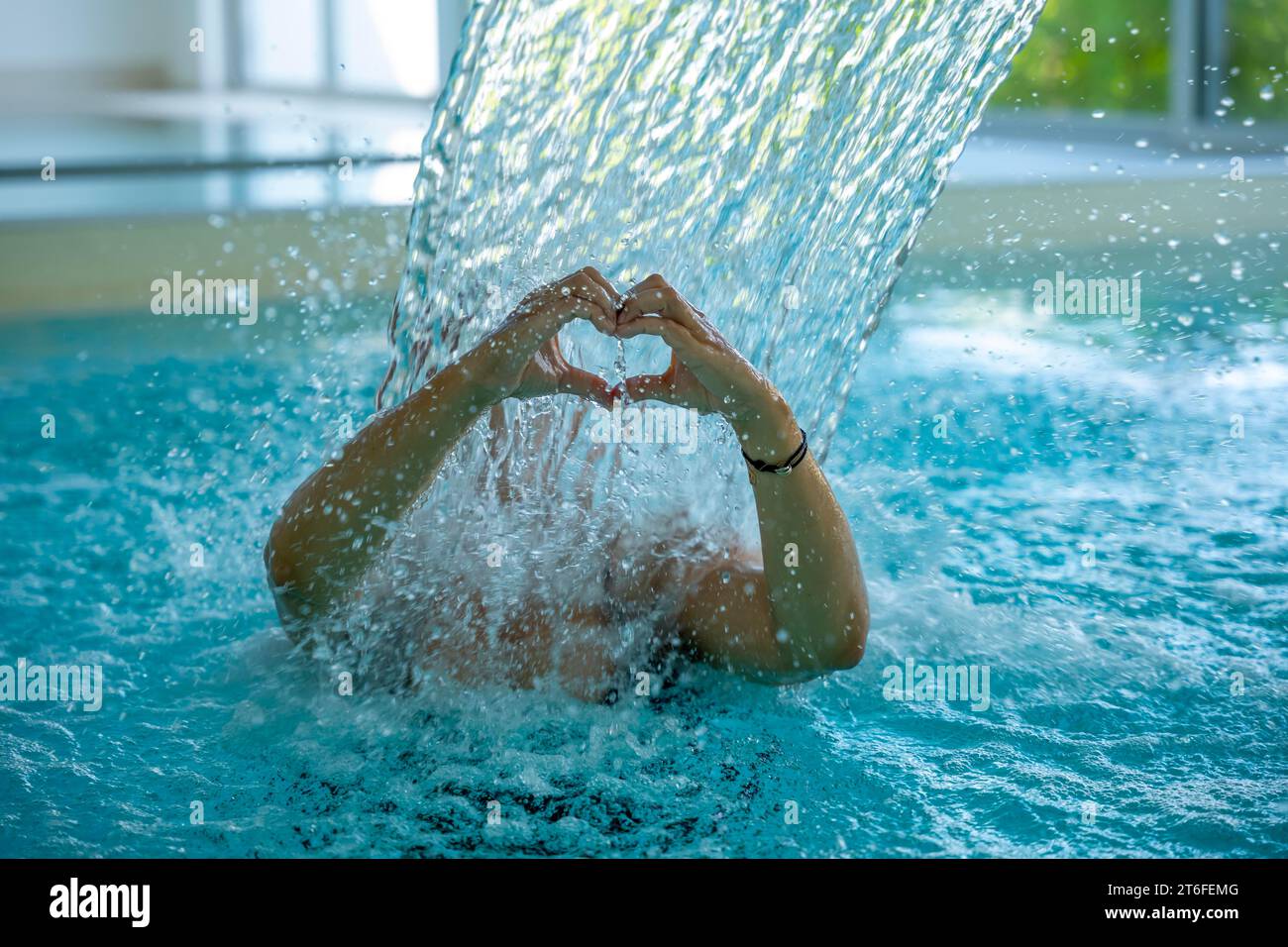 Woman Behind a Waterfall in a SPA Swimming Pool and Making a Heart ...