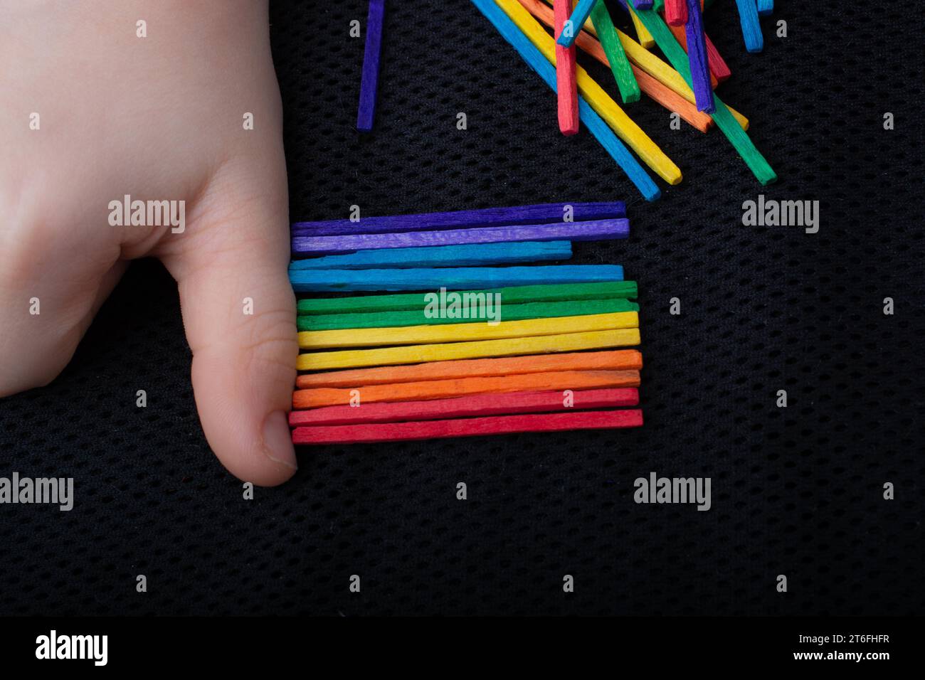 Kid playing with coloured wooden sticks for creativity on white ...