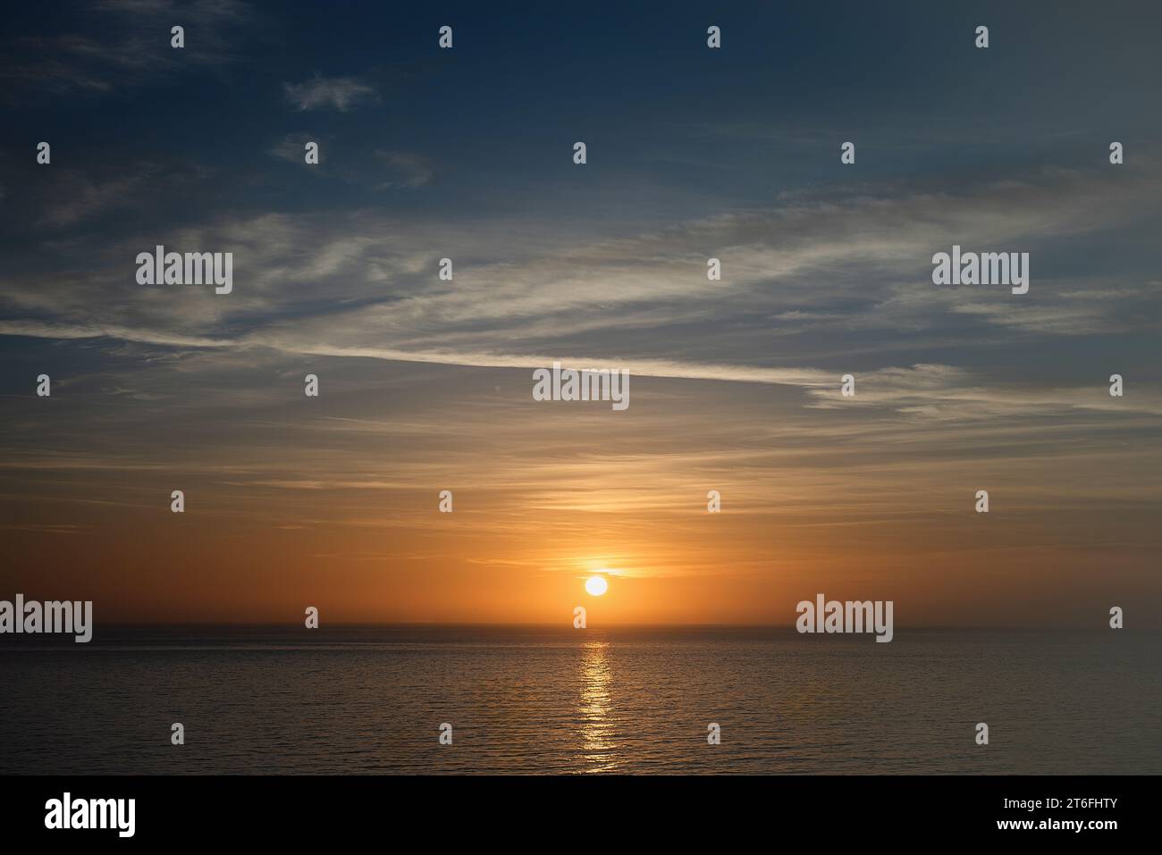 Sunset sky clouds vertical over sea in the evening with colorful orange ...