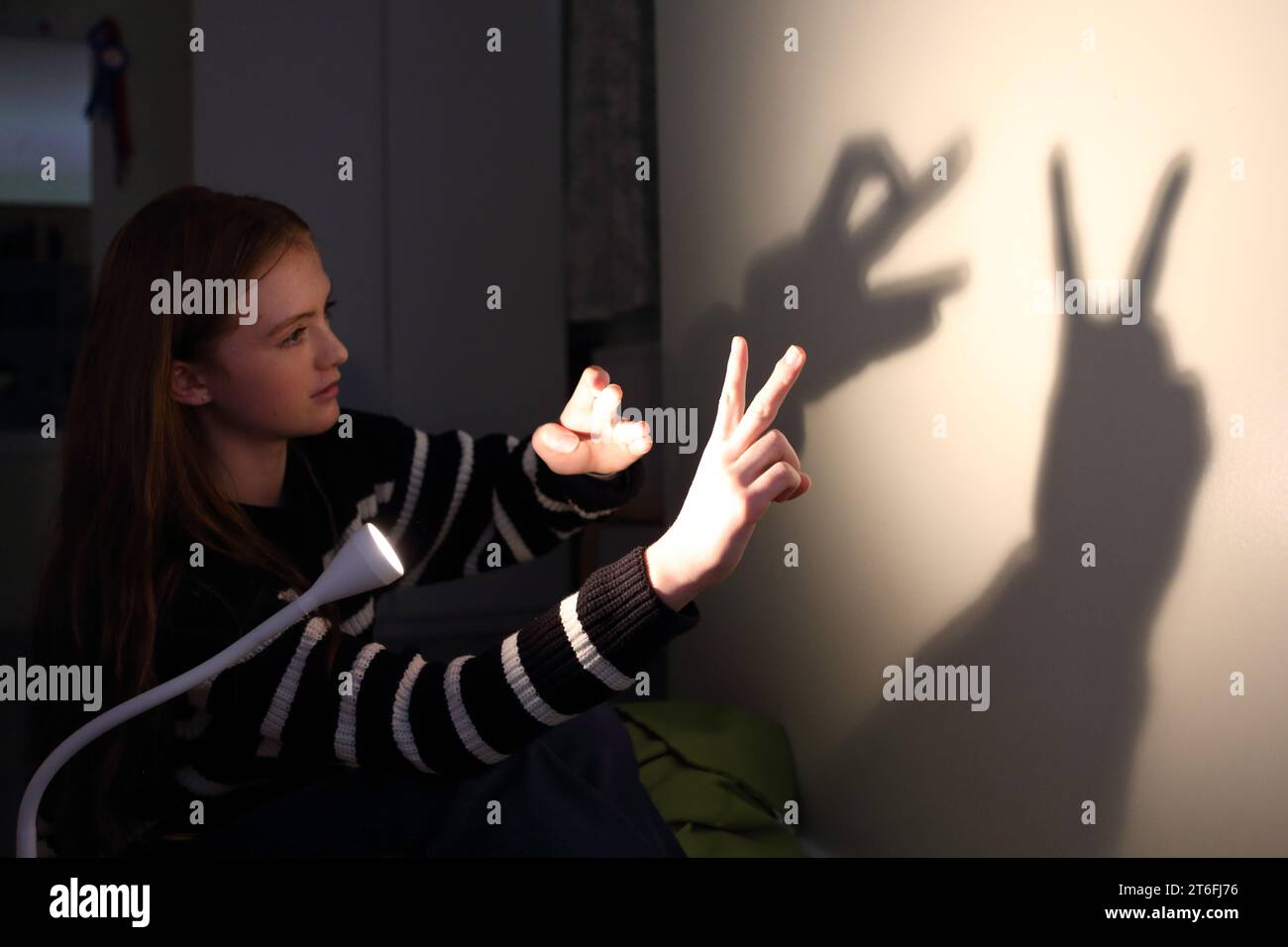 Teenage girl casting shadow puppet shapes with her hands and fingers ...
