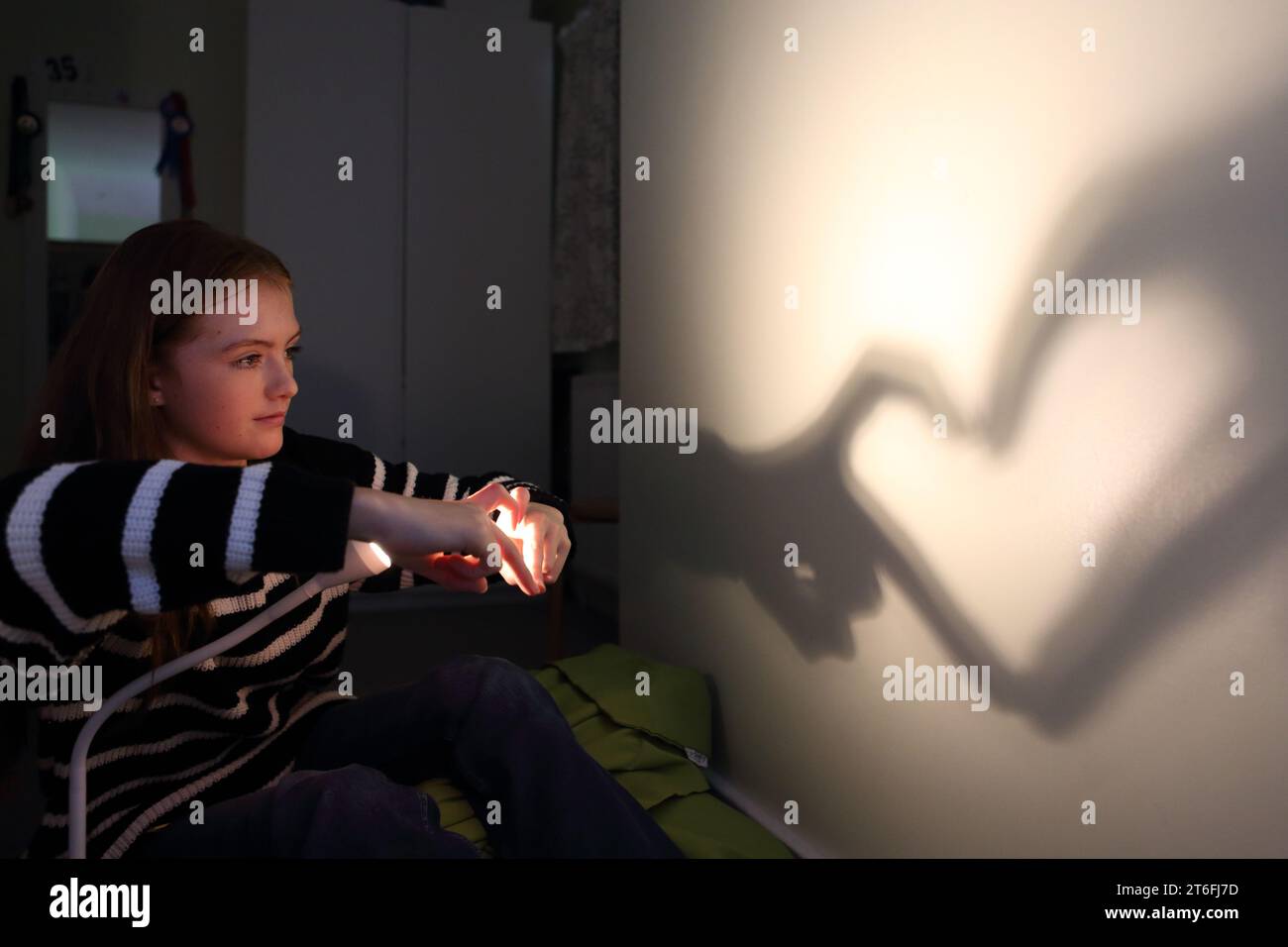 Teenage girl making shadow heart shape with her hands and fingers with ...