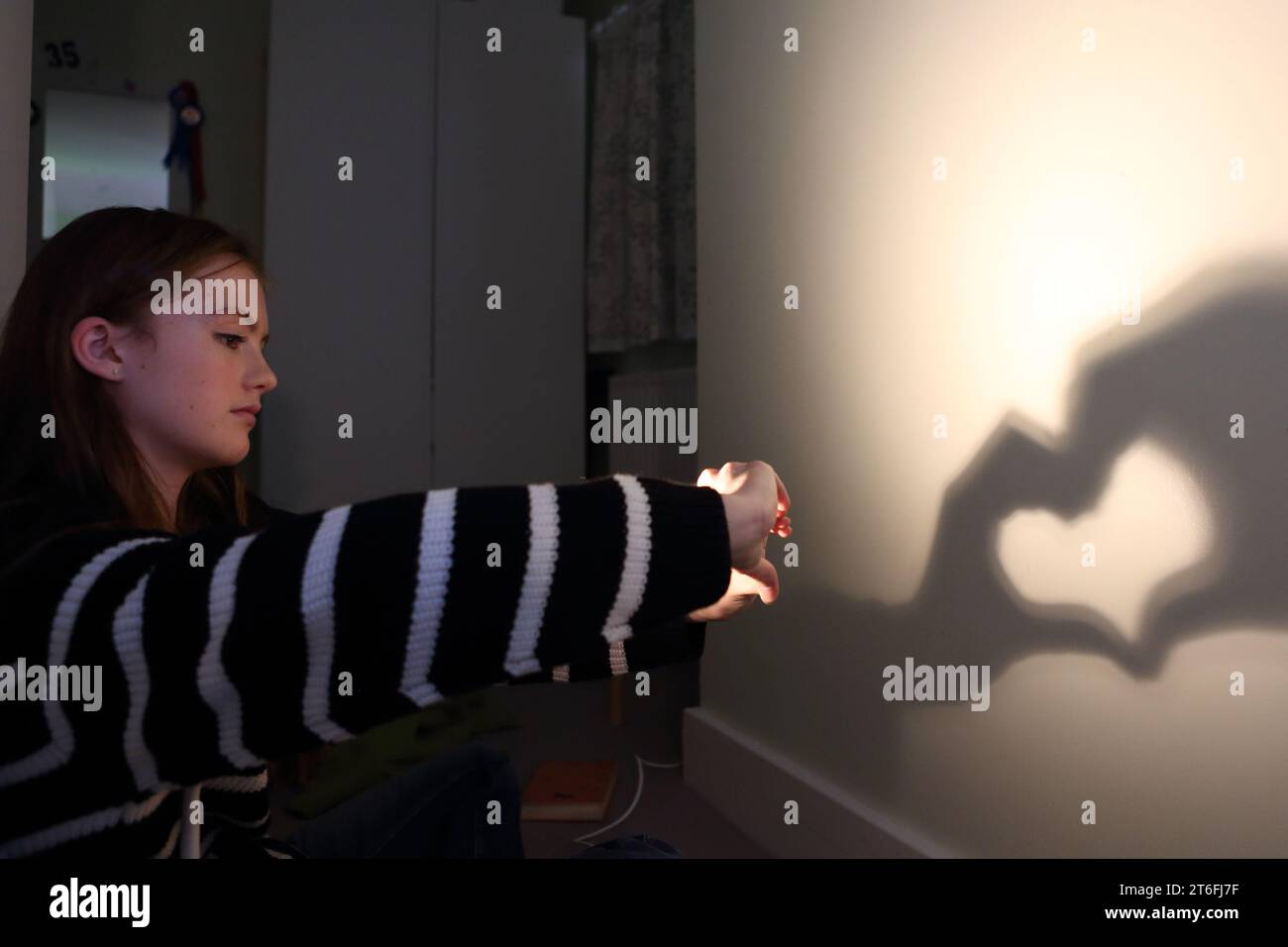 Teenage girl making shadow heart shape with her hands and fingers with ...