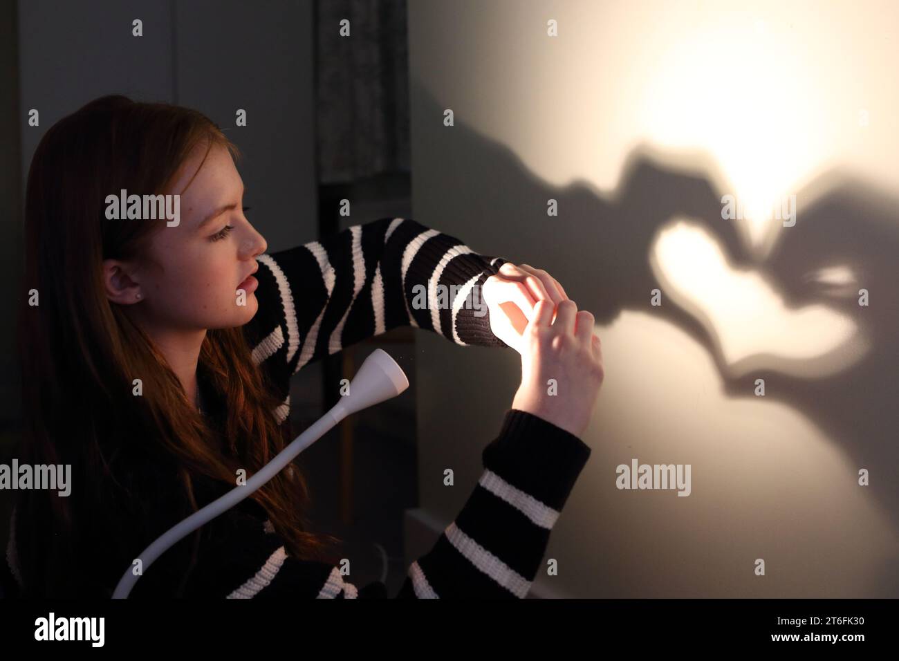 Teenage girl making shadow heart emoji shape with her hands and fingers ...