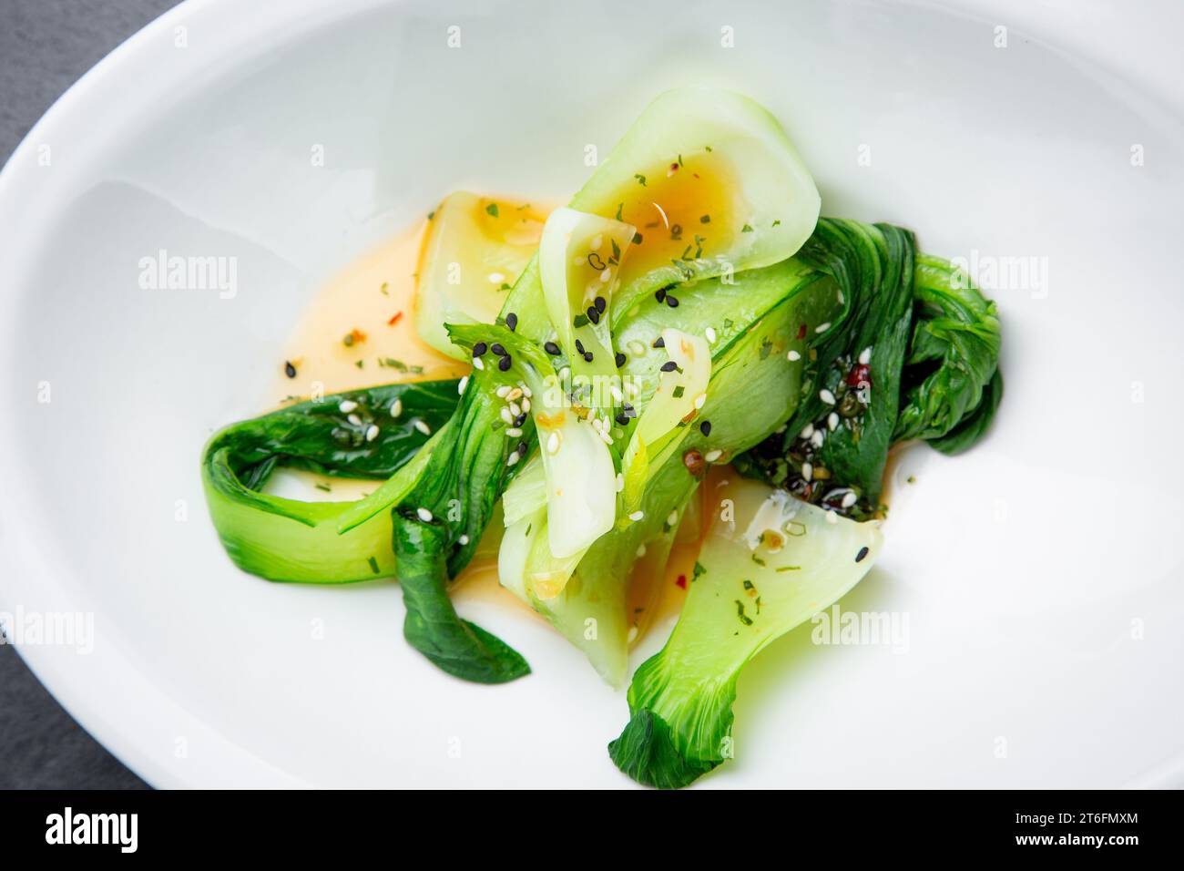bok choy cabbage with sesame seeds and sauce in a white plate, top view ...