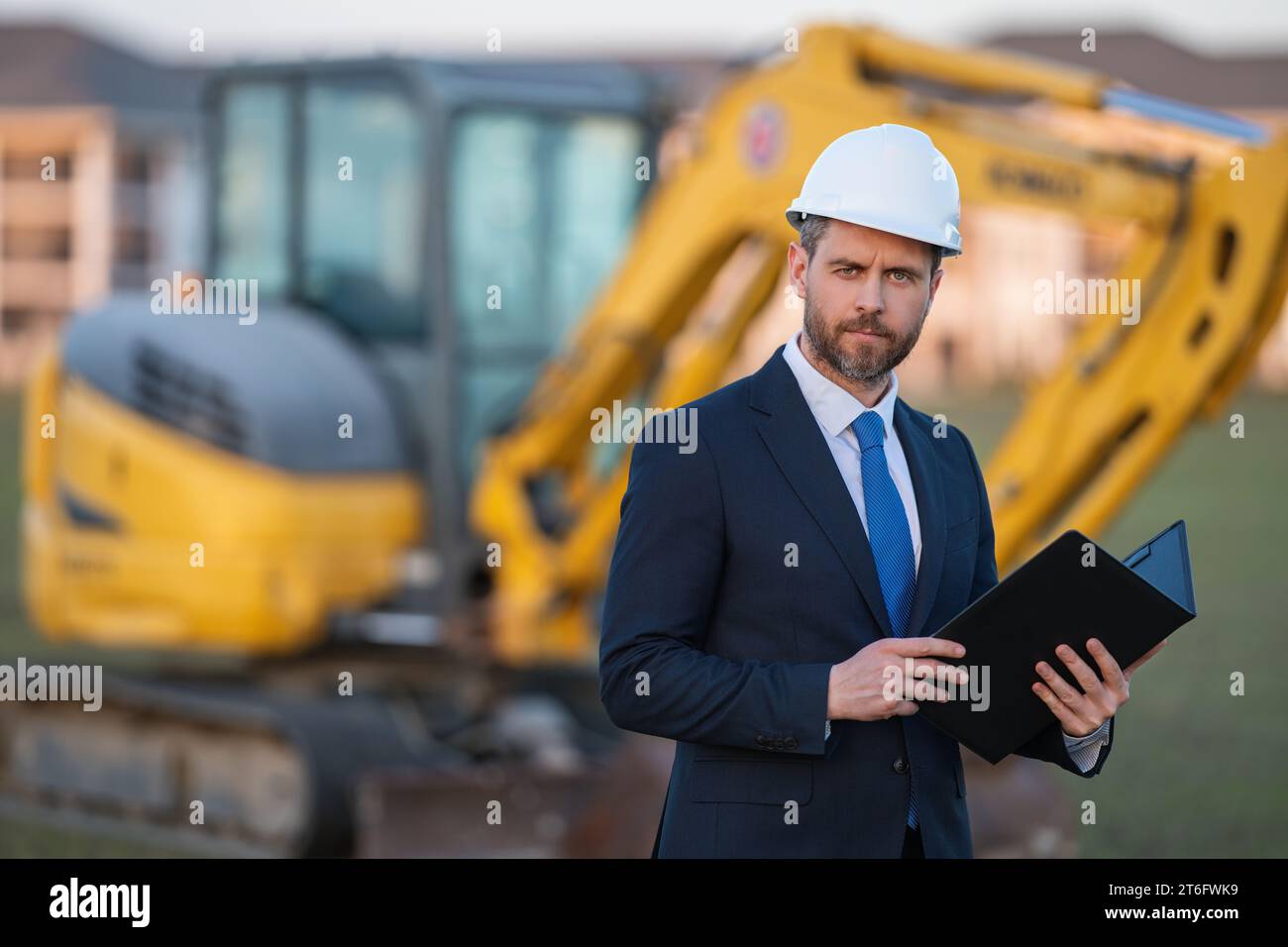 Construction owner near excavator. Confident construction owner in ...