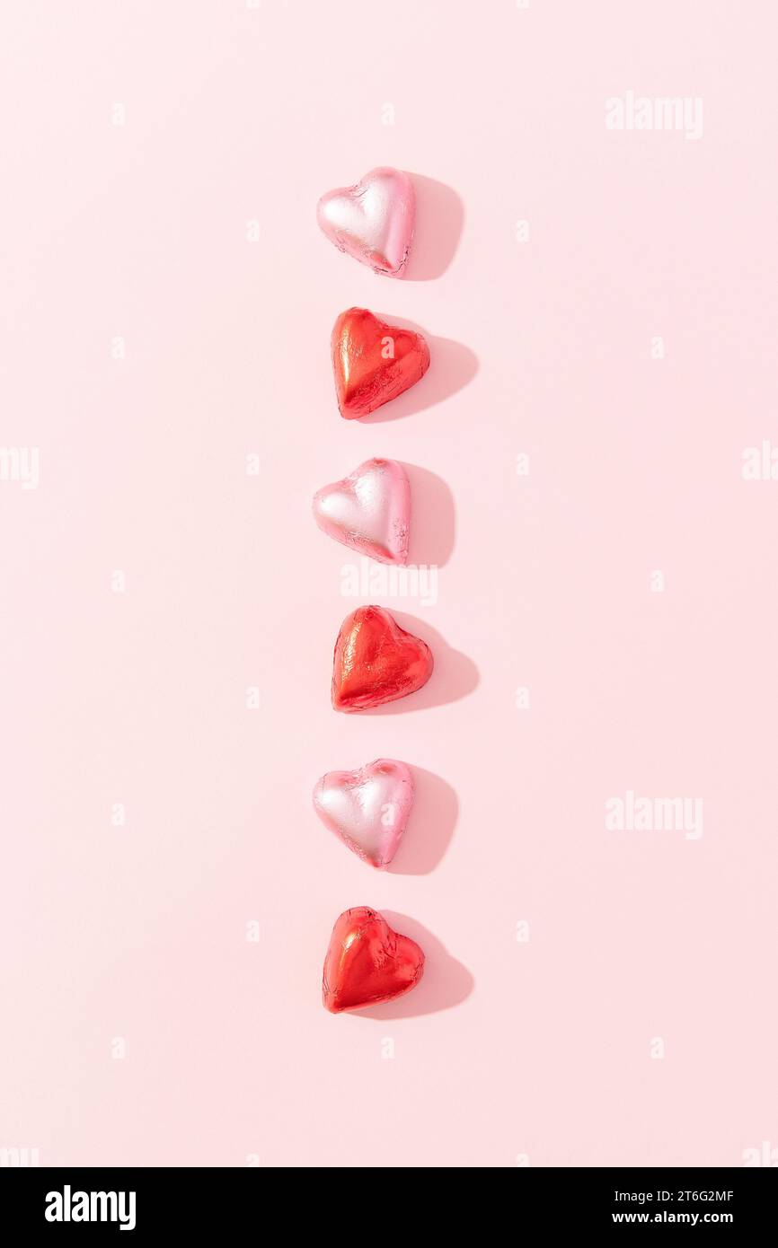 Vertical line made of heart shaped chocolate candies on pink background ...