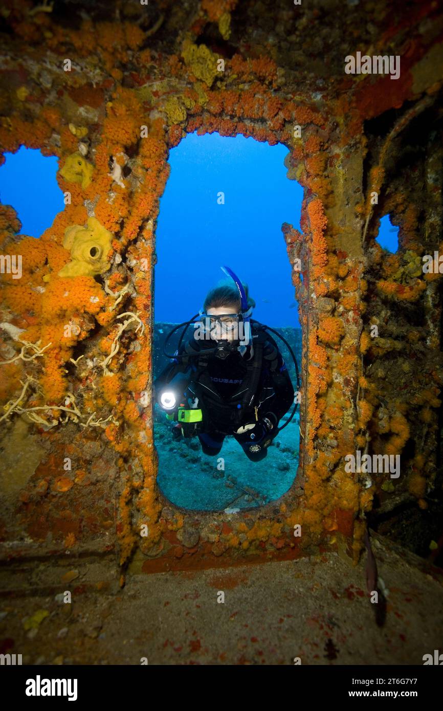 Female scuba diver shines underwater light through doorway on the ...