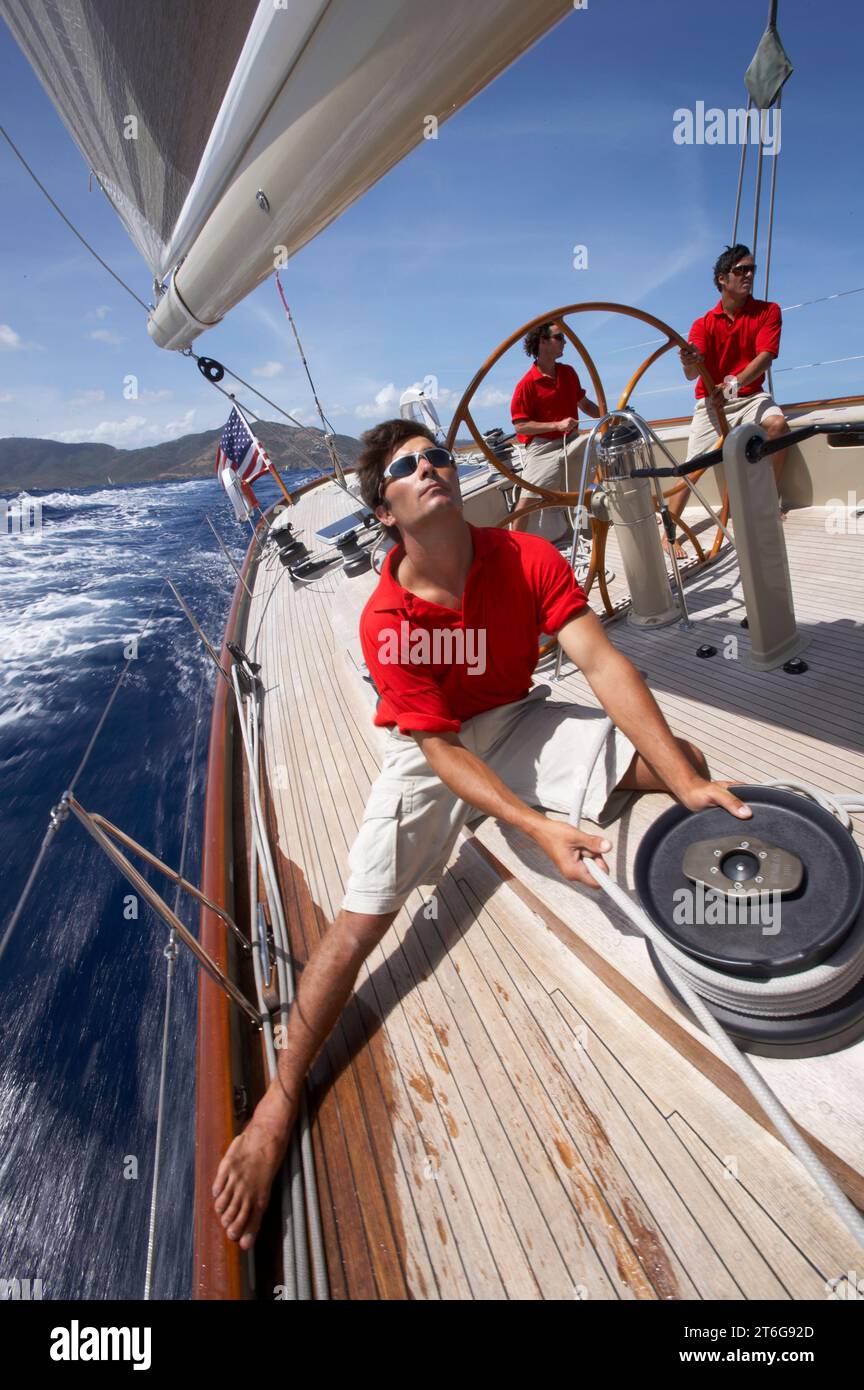 Brett trims the jib sheet, sailing on board a classic racing sloop ...