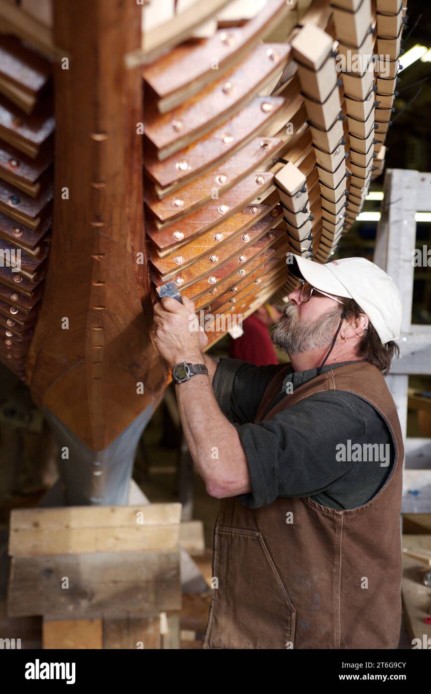 A boat builder works on the hull of a yacht being built in Rockport ...