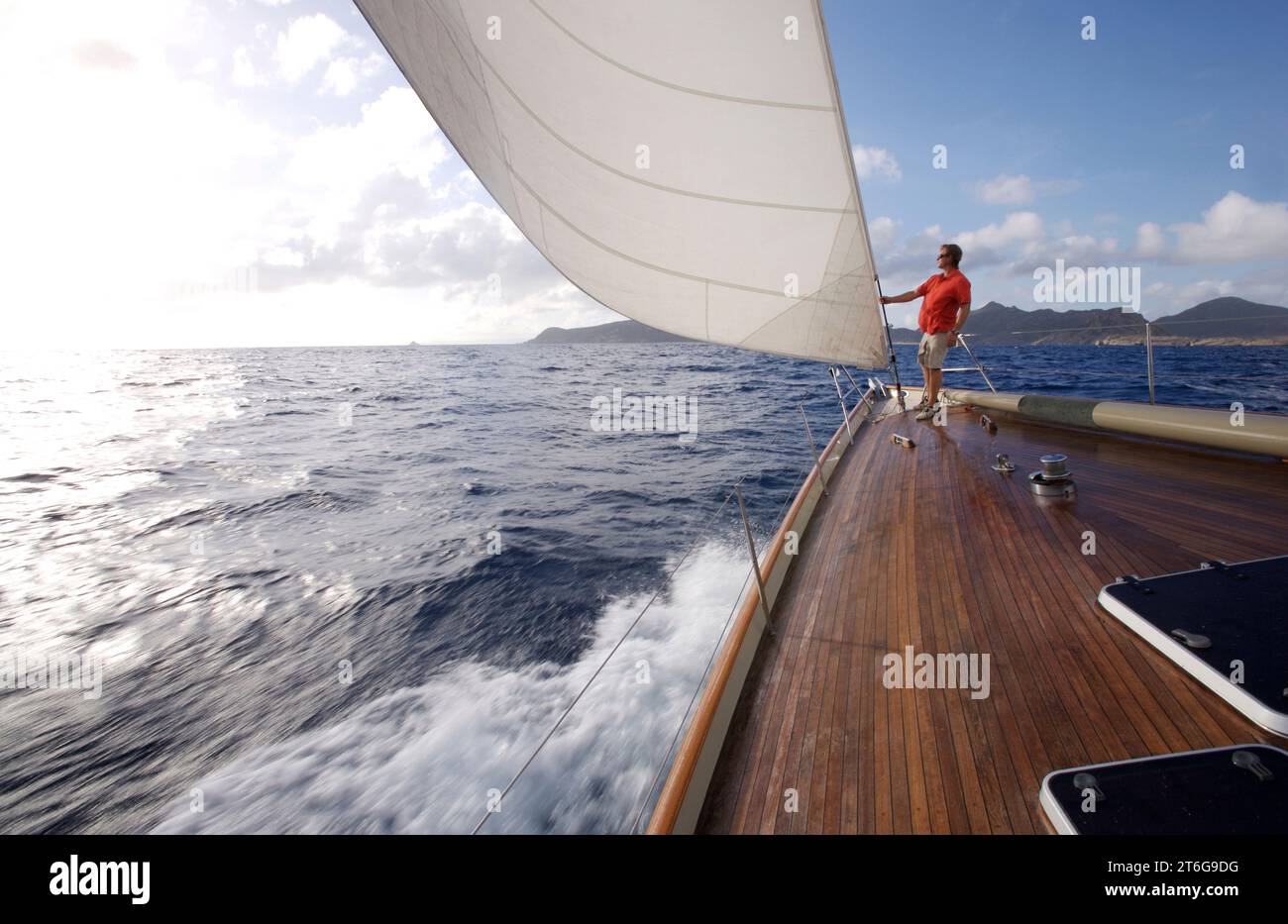 A man stands on the bow of a yacht while sailing near St. Bartholomew ...