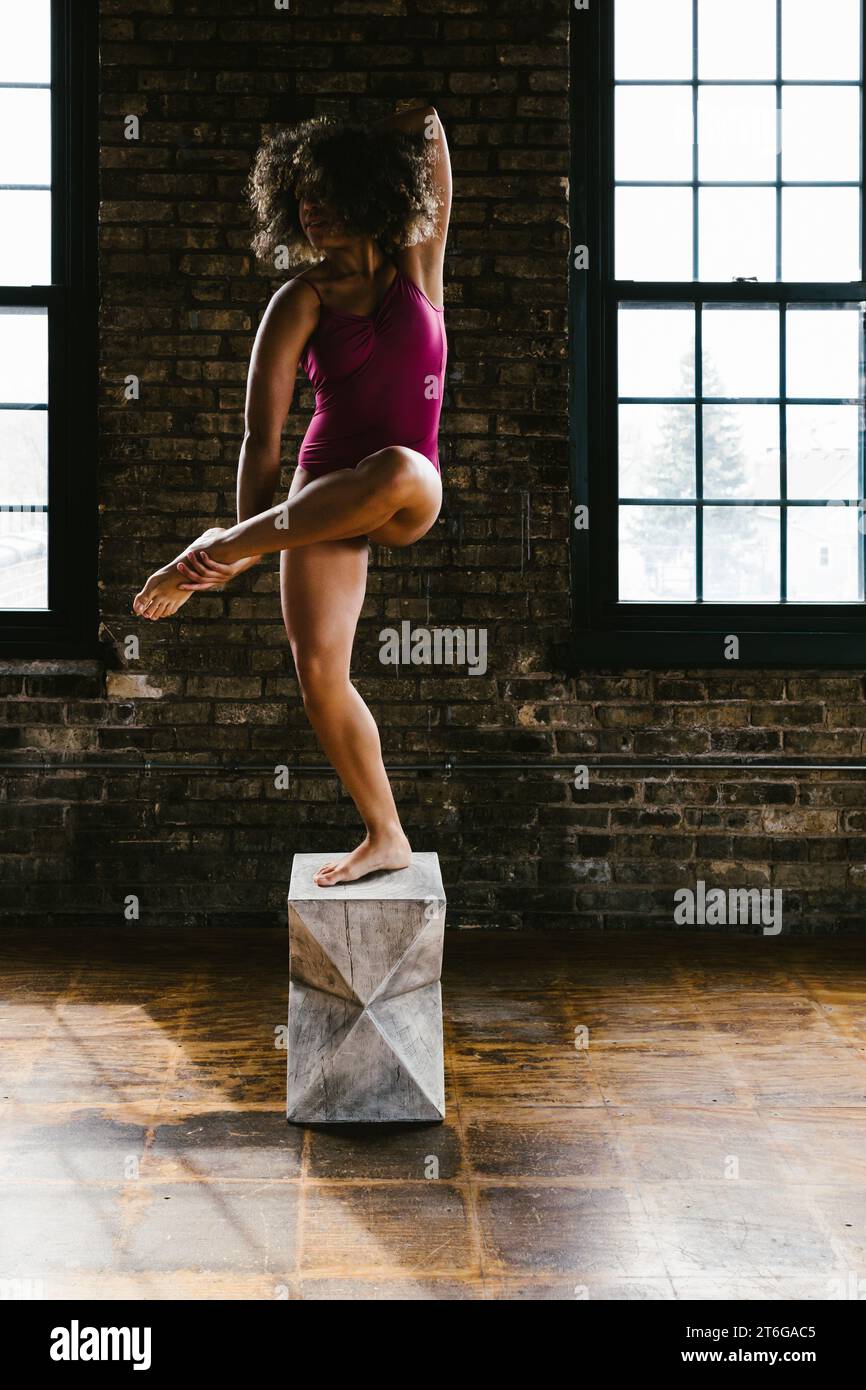 Woman dancer with curly hair poses on block with exposed brick Stock ...