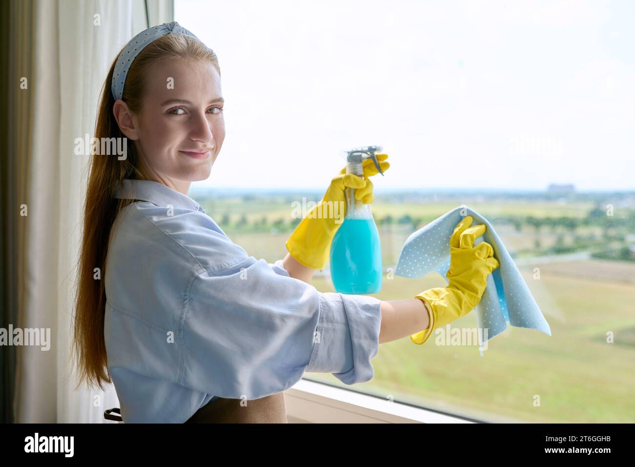Young woman cleaning windows using spray and rag Stock Photo - Alamy