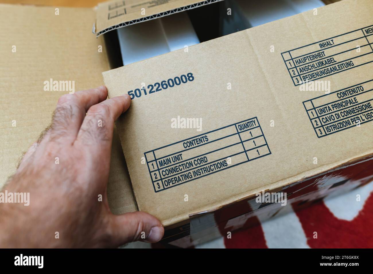 A cardboard box opens to reveal the main unit, connection cord, and ...