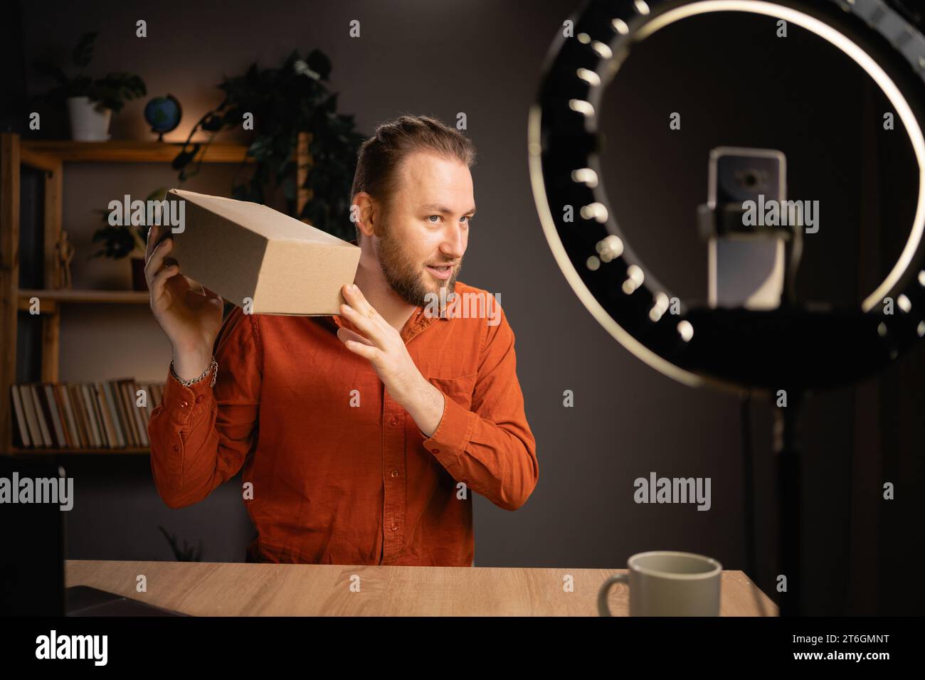 Attractive man filming on digital camera unpacking process of cardboard ...