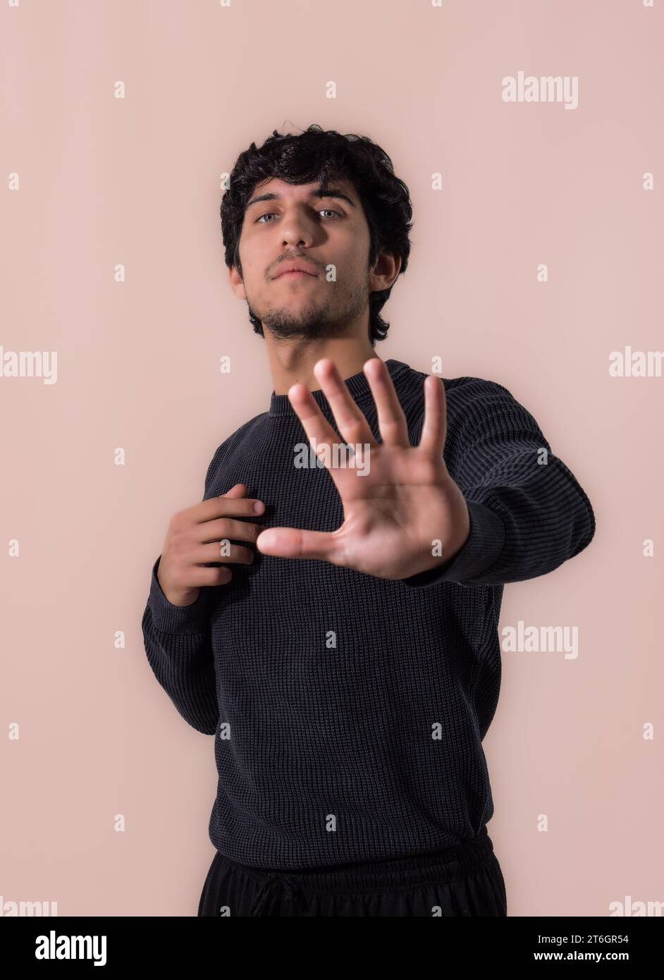 A man making a stop sign with his hands, towards the camera, in studio ...