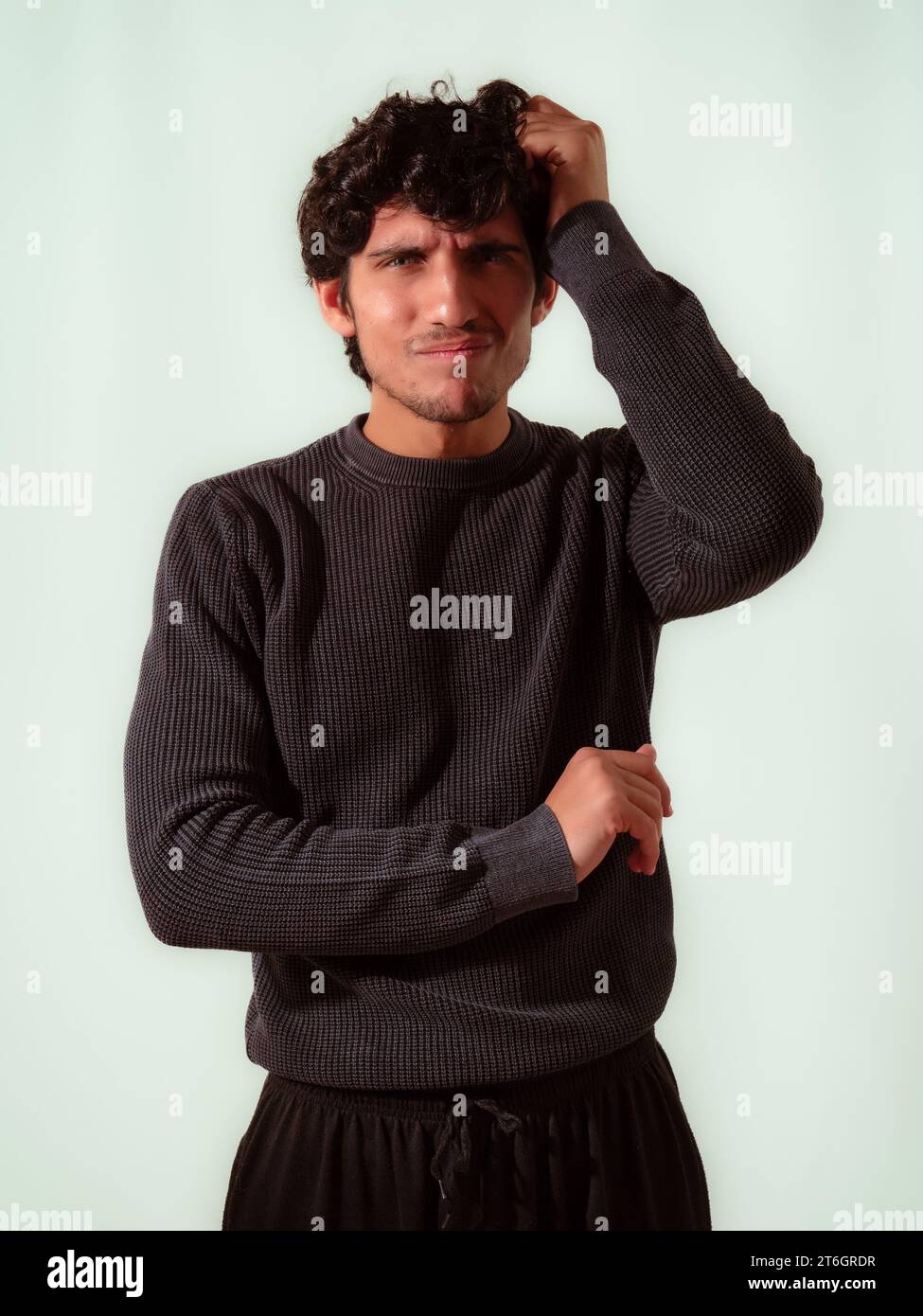 A young attractive man with curly hair is posing for a picture, with a ...