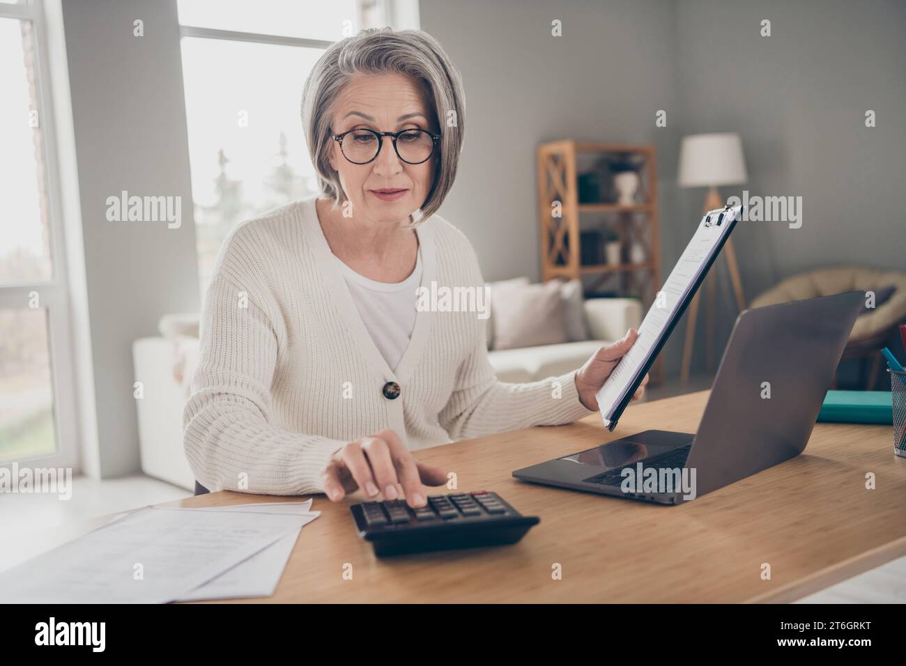Photo of charming smart elderly lady ceo wear white calculate salary ...