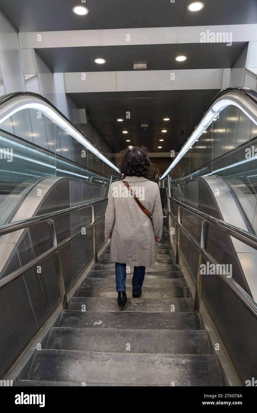 Woman from behind descending staircase in between escalators to train, metro, tube, Malaga ...
