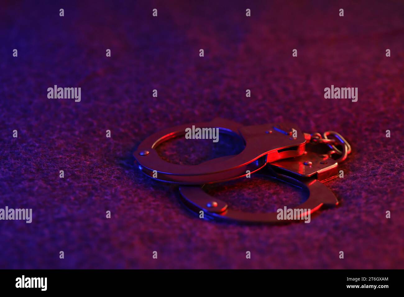 Closed handcuffs on the dark surface at night with police car lights ...