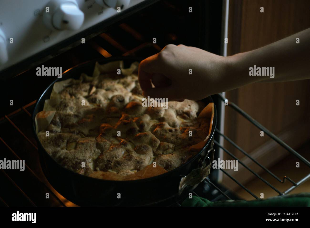 Female hands check the readiness of Charlotte's apple pie and open the ...