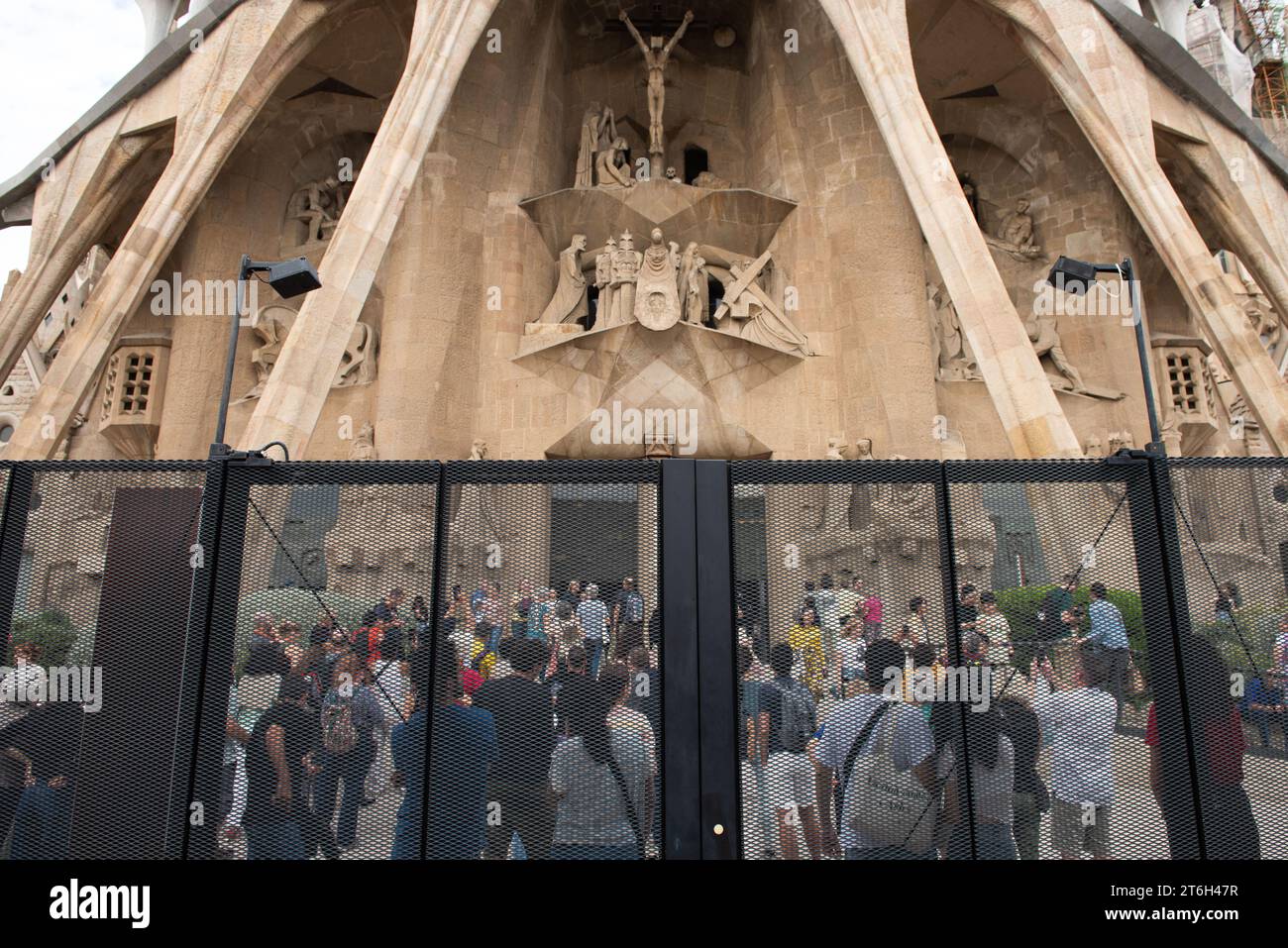 A crowd of tourists behind the fence of the Sagrada Familia, cathedral ...