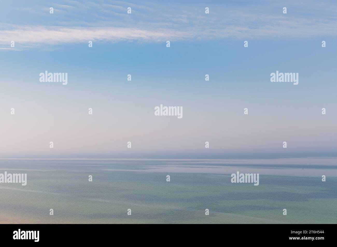 Blue sky with haze and blurry glowing pink clouds above the sea ...