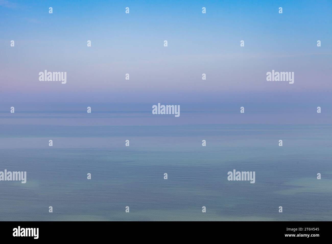 Blue sky with haze and blurry glowing pink clouds above the sea ...