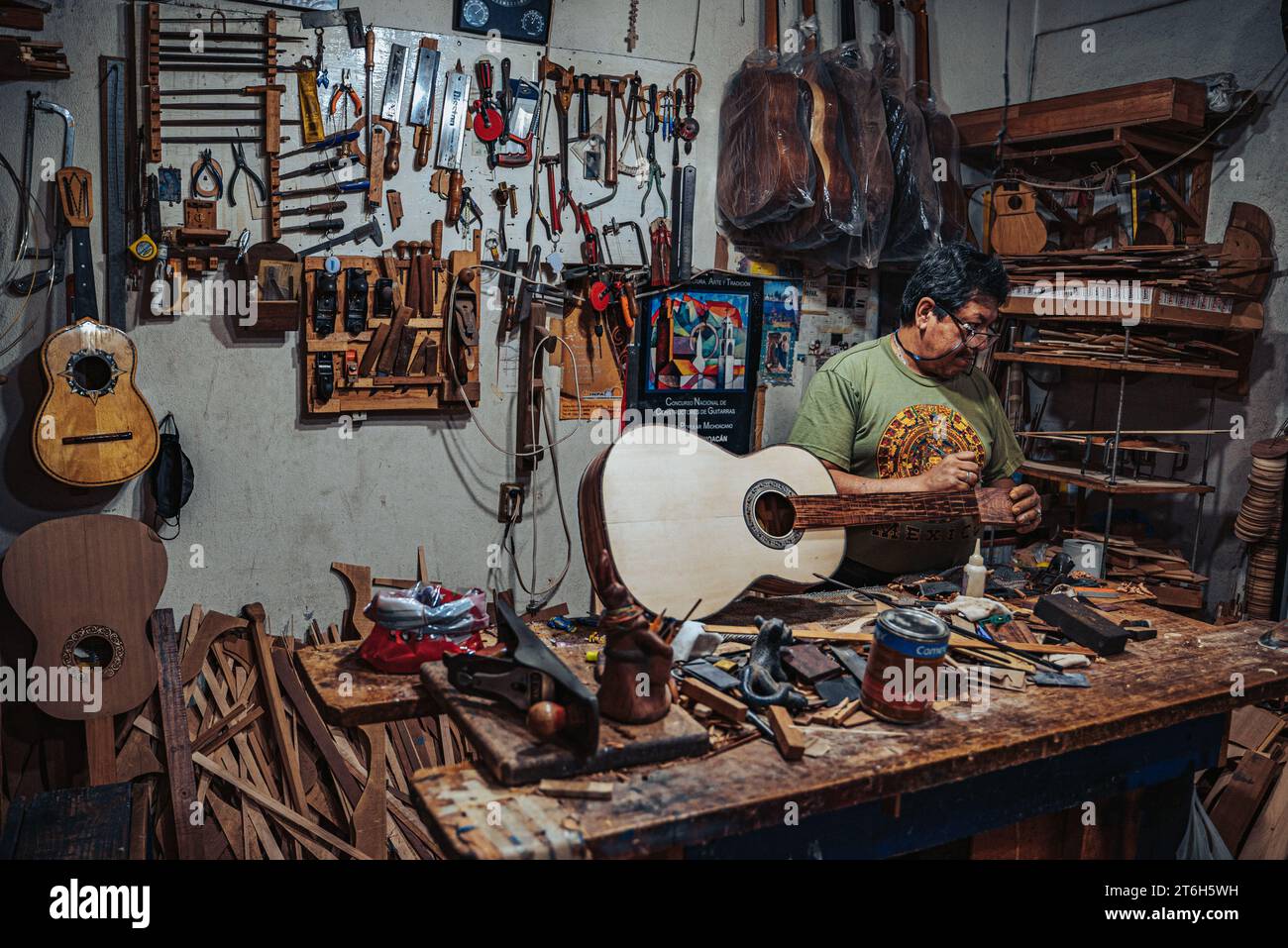 A person in a garage working on a guitar surrounded by a vast array of ...