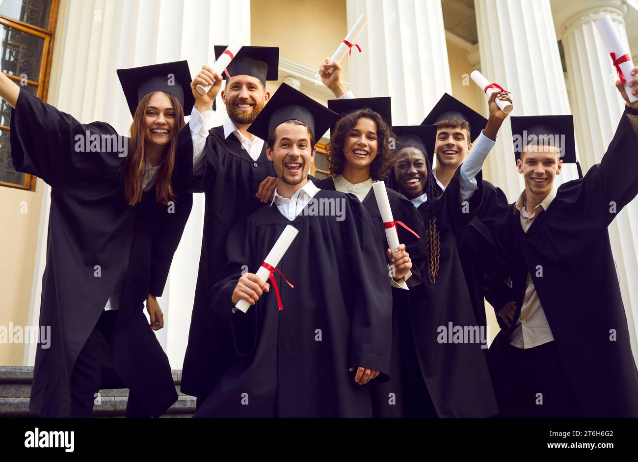 Group of happy university students with diplomas standing together near ...