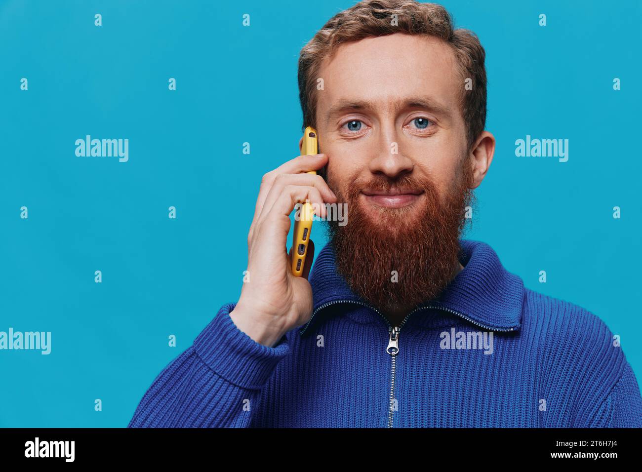 Portrait of a man with a phone in his hands talking, calling, on a blue ...
