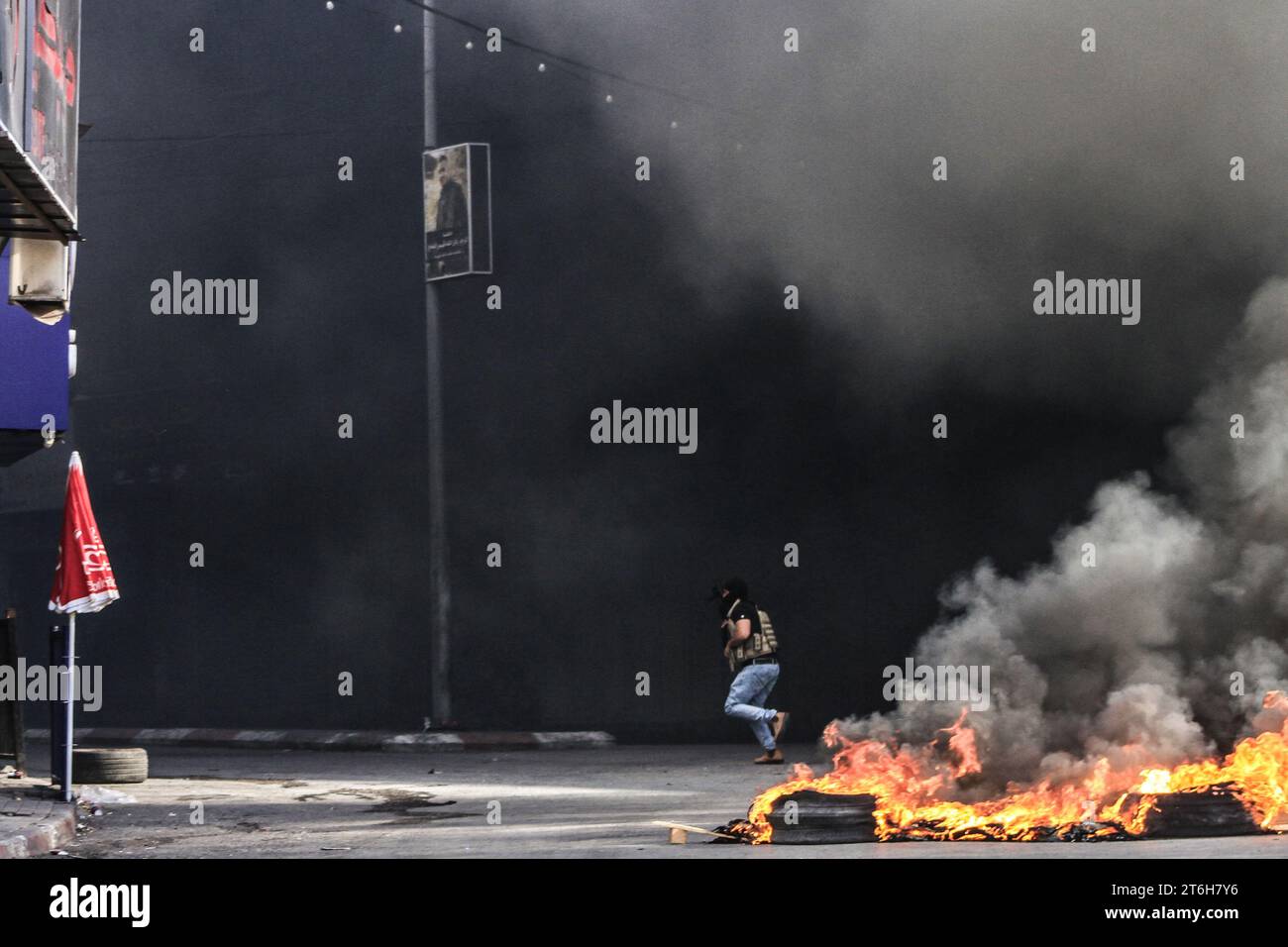 A masked Palestinian gunman takes cover amid flames of burning tires ...