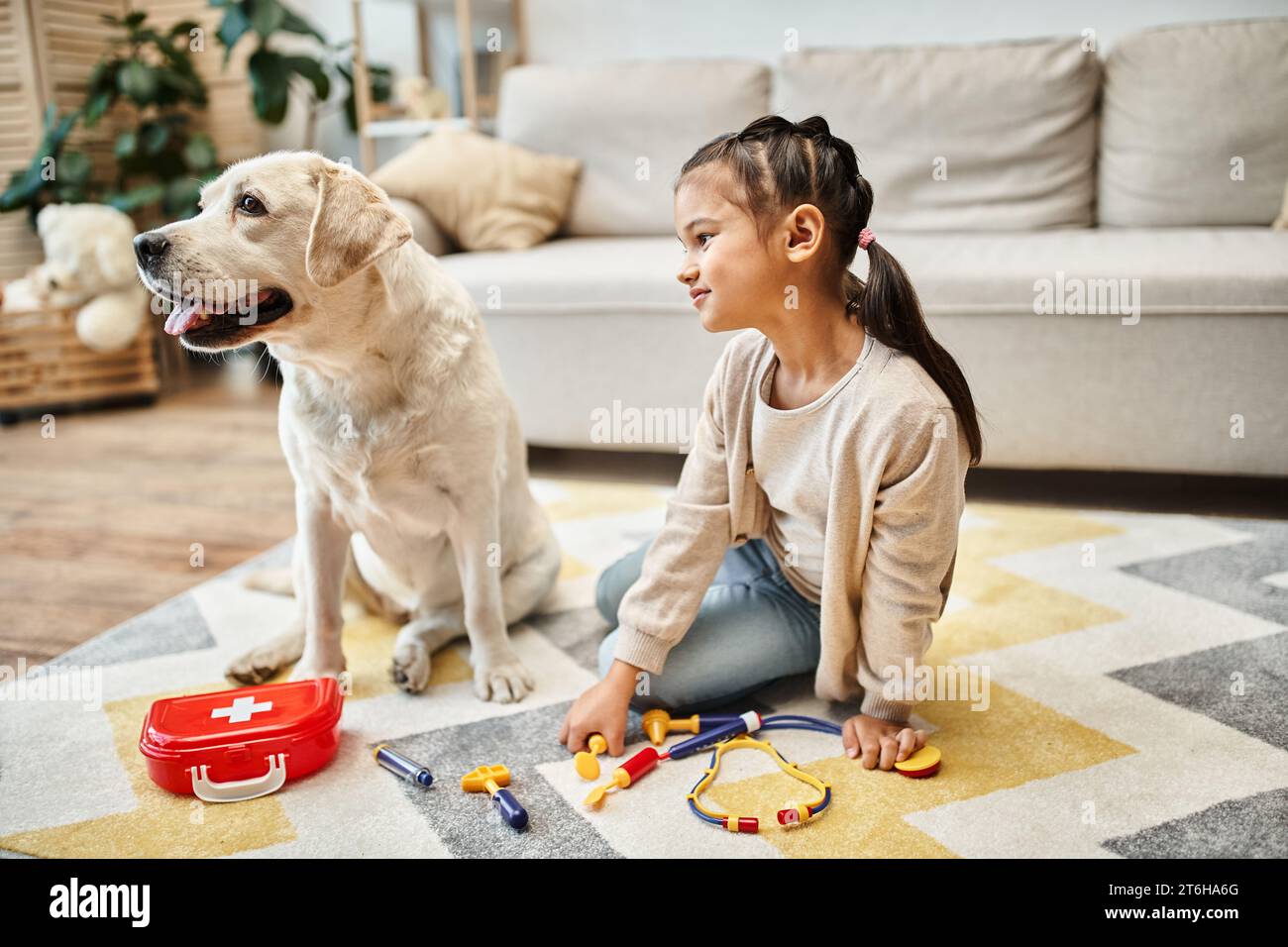happy girl in casual attire playing doctor with labrador in modern ...