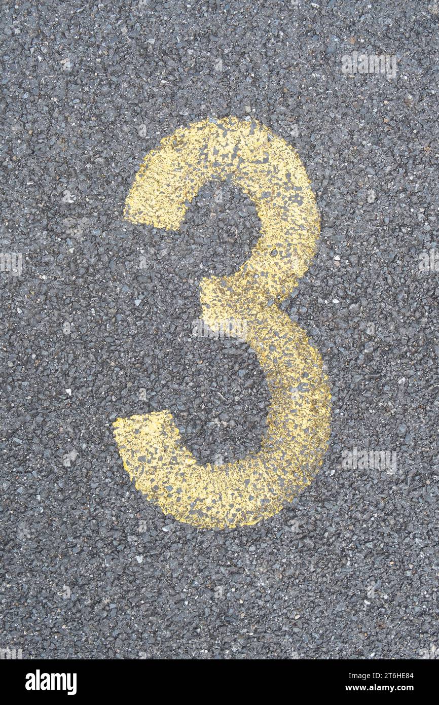the number 3 three are drawn with color paint on asphalt. a children's ...