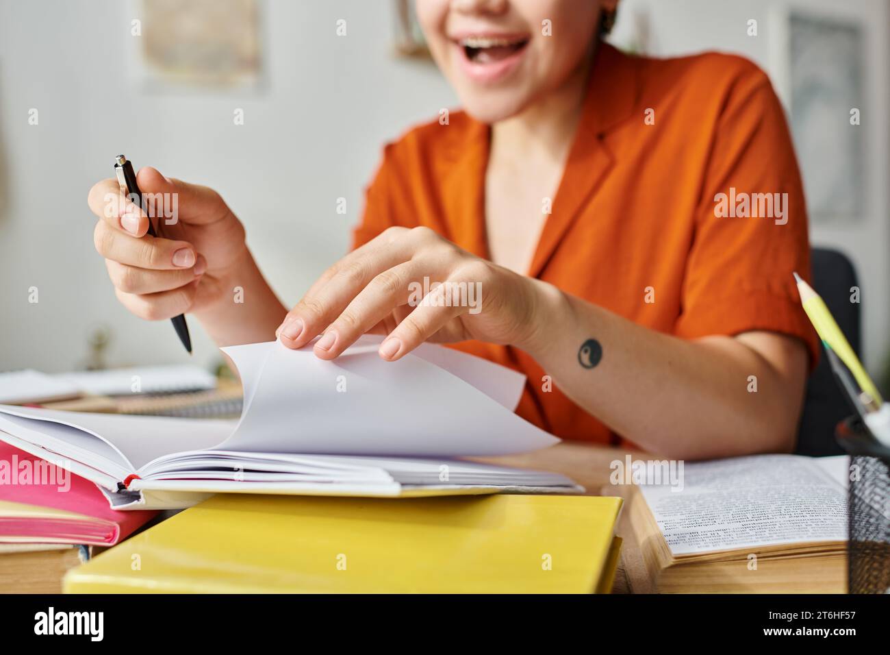 cropped view of cheerful young student turning textbook pages and ...
