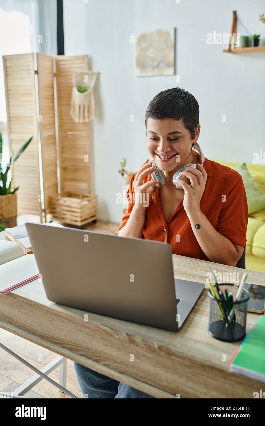 vertical shot of cheerful student in front of laptop attending online ...